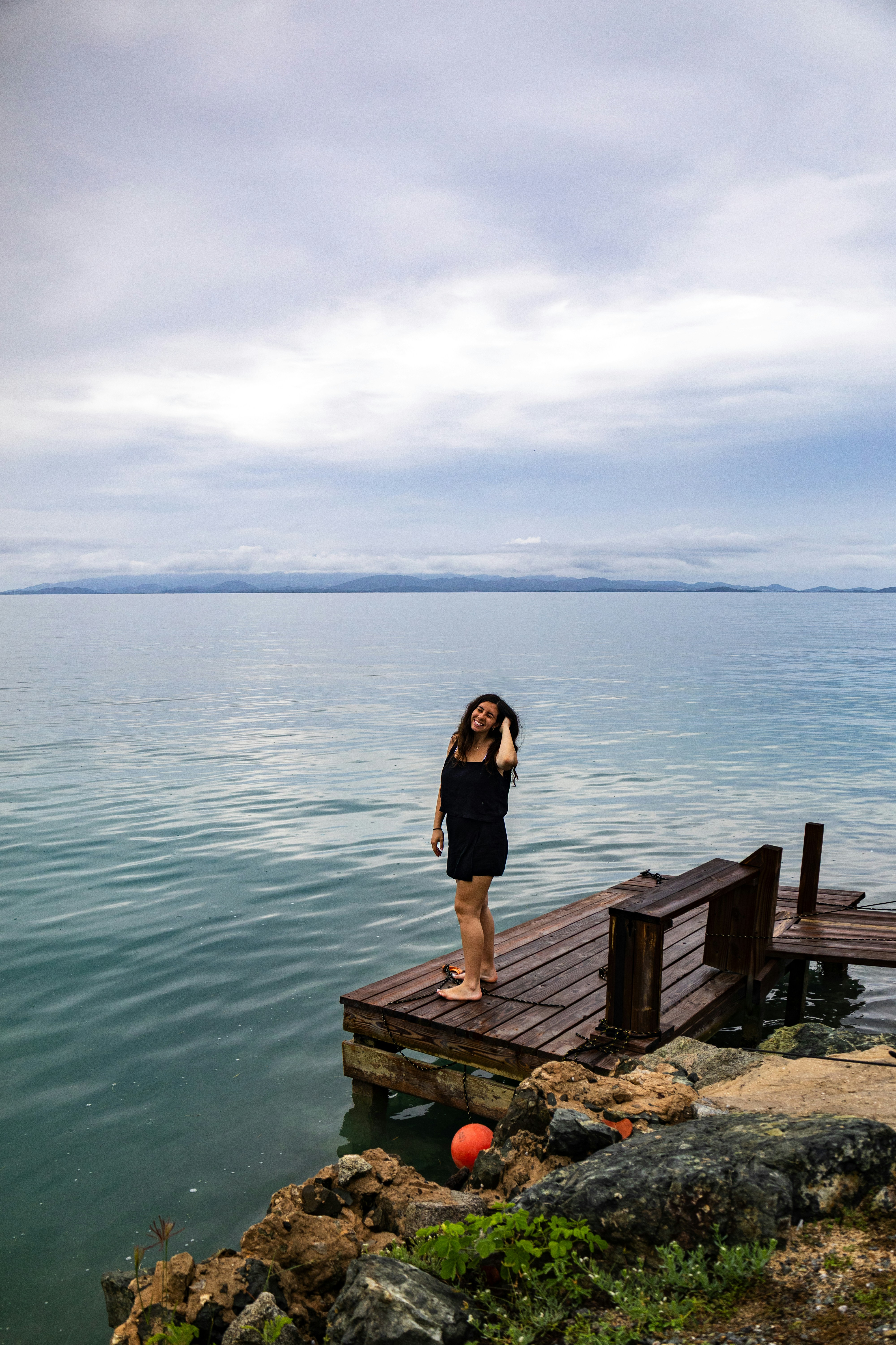 Edge of Turquoise Calm: A Solitary Figure on the Wooden Dock
