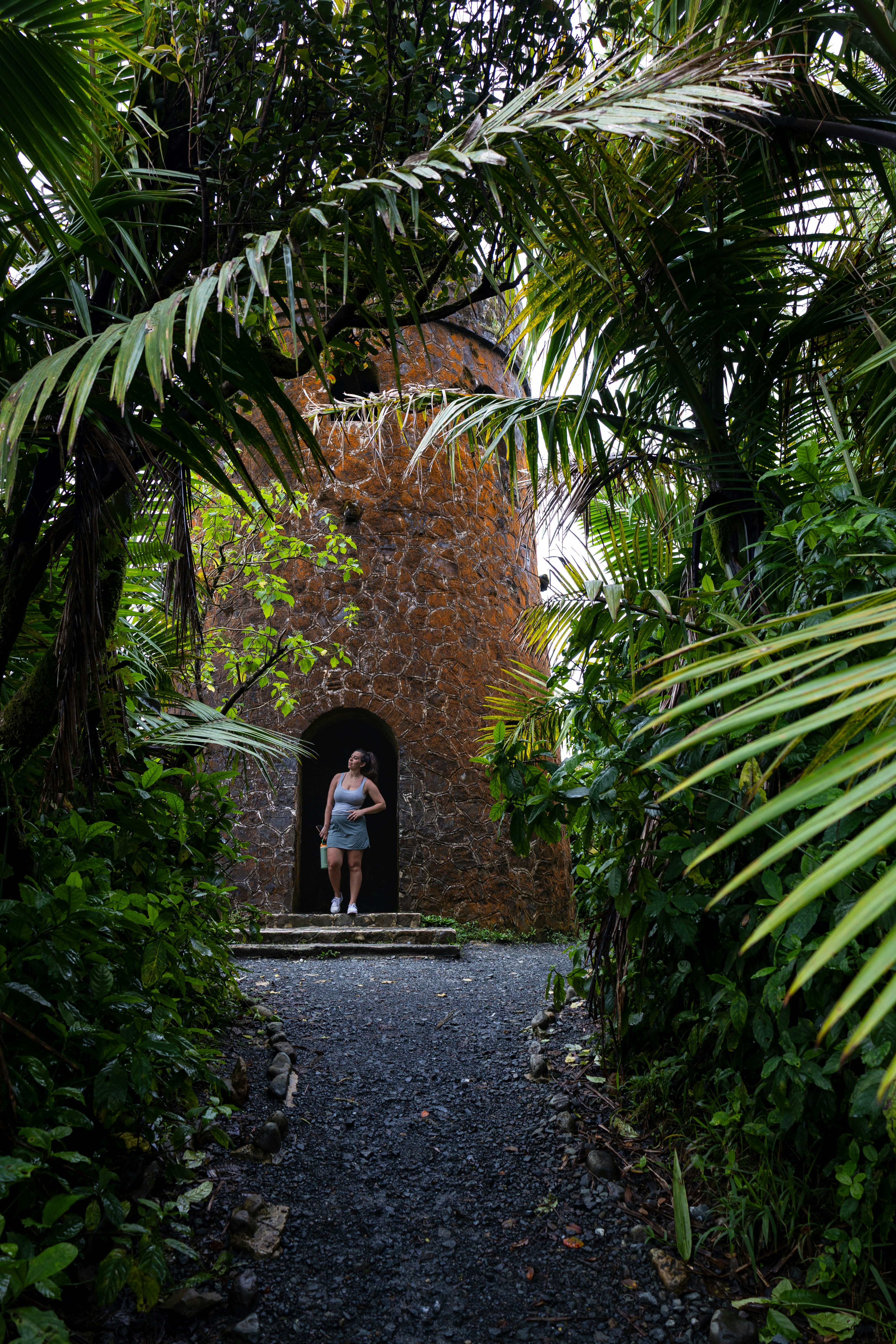 Hidden Entrance: A Woman Waiting at the Stone Turret in a Lush Corridor