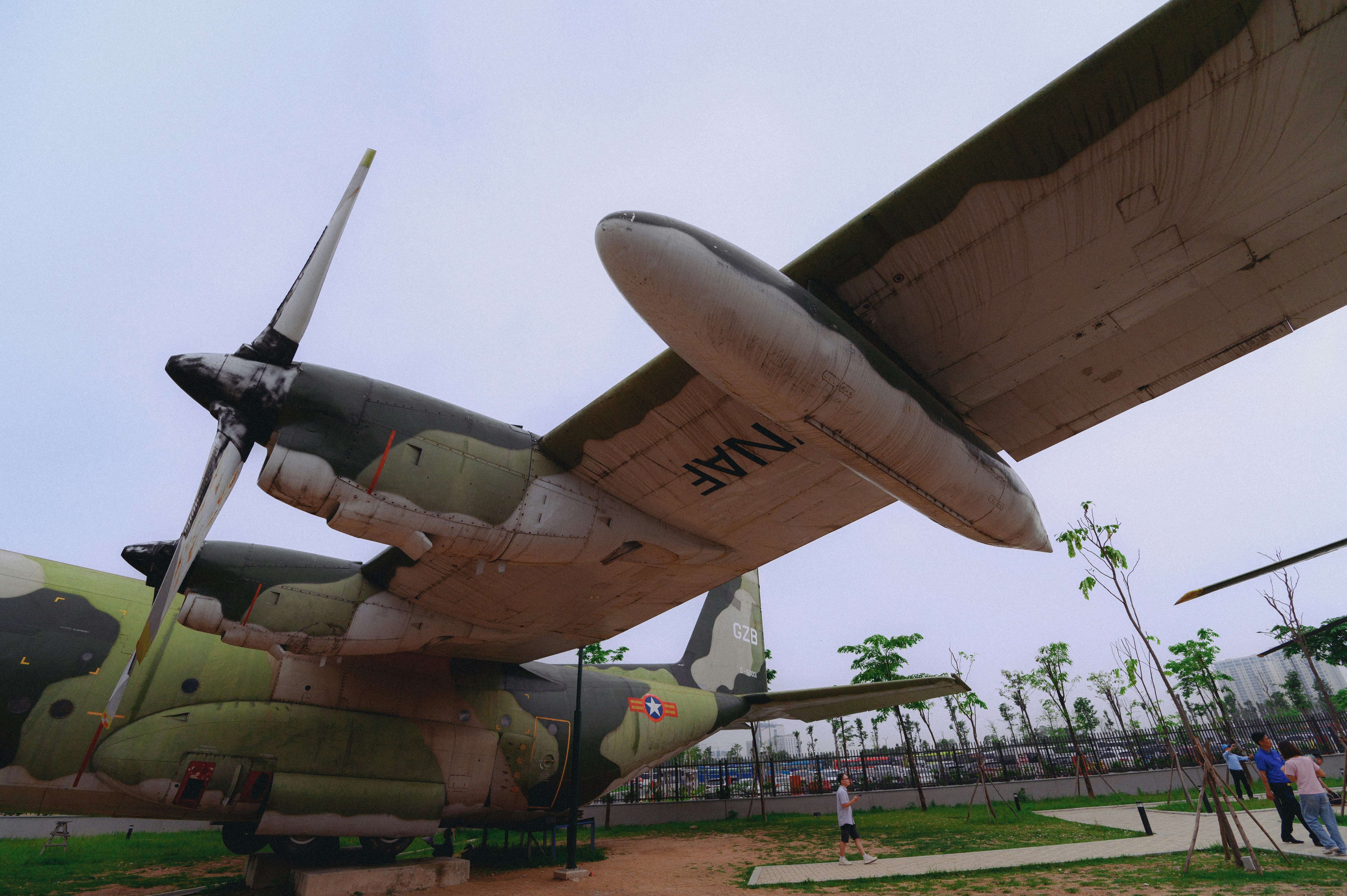 Green Camouflage Cargo Plane on Public Display: A Prop-Driven Military Transport Dominating the Park Lawn