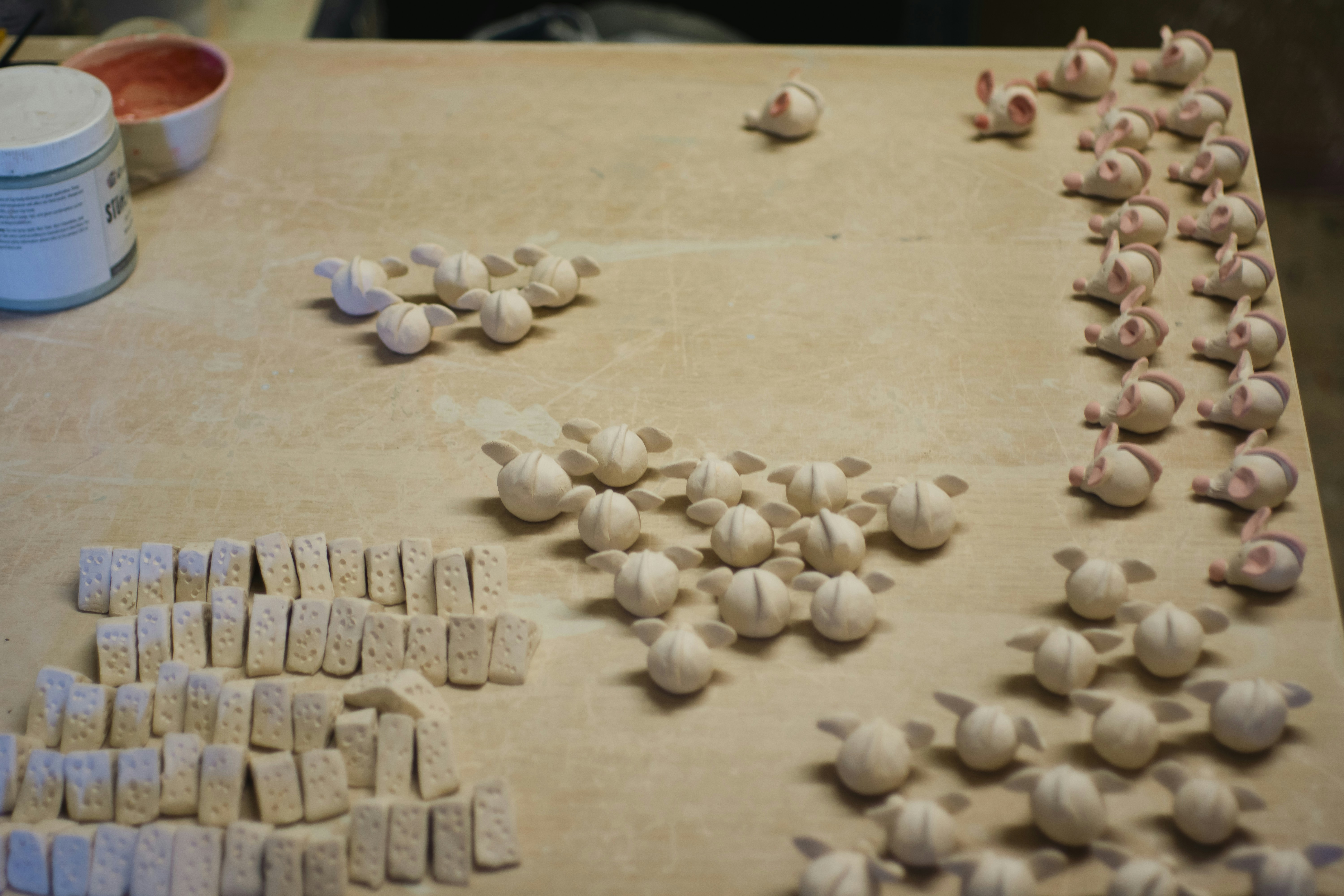 Miniature Grid and Curve: White Orbs and Pink-Tipped Figures on Wood