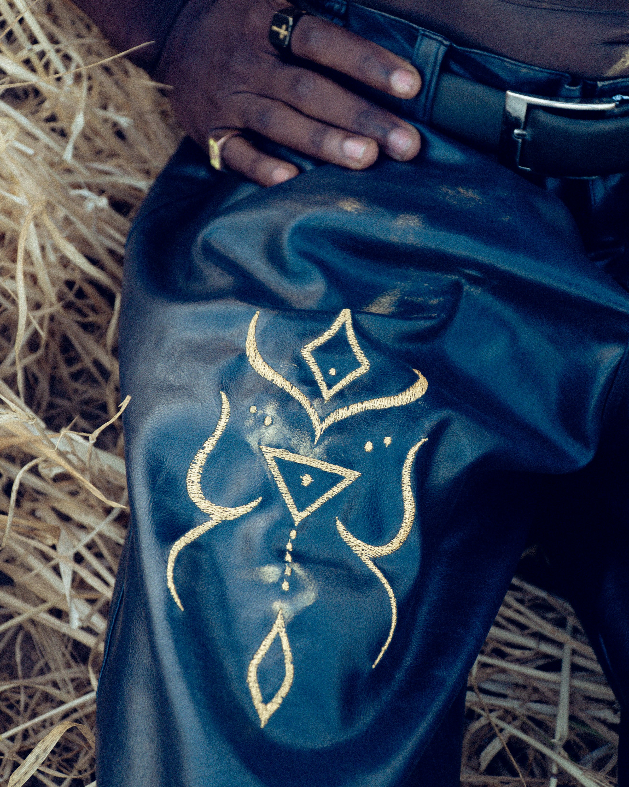 Glyphs in Blue: a close-up of gold embroidery on cobalt leather trousers