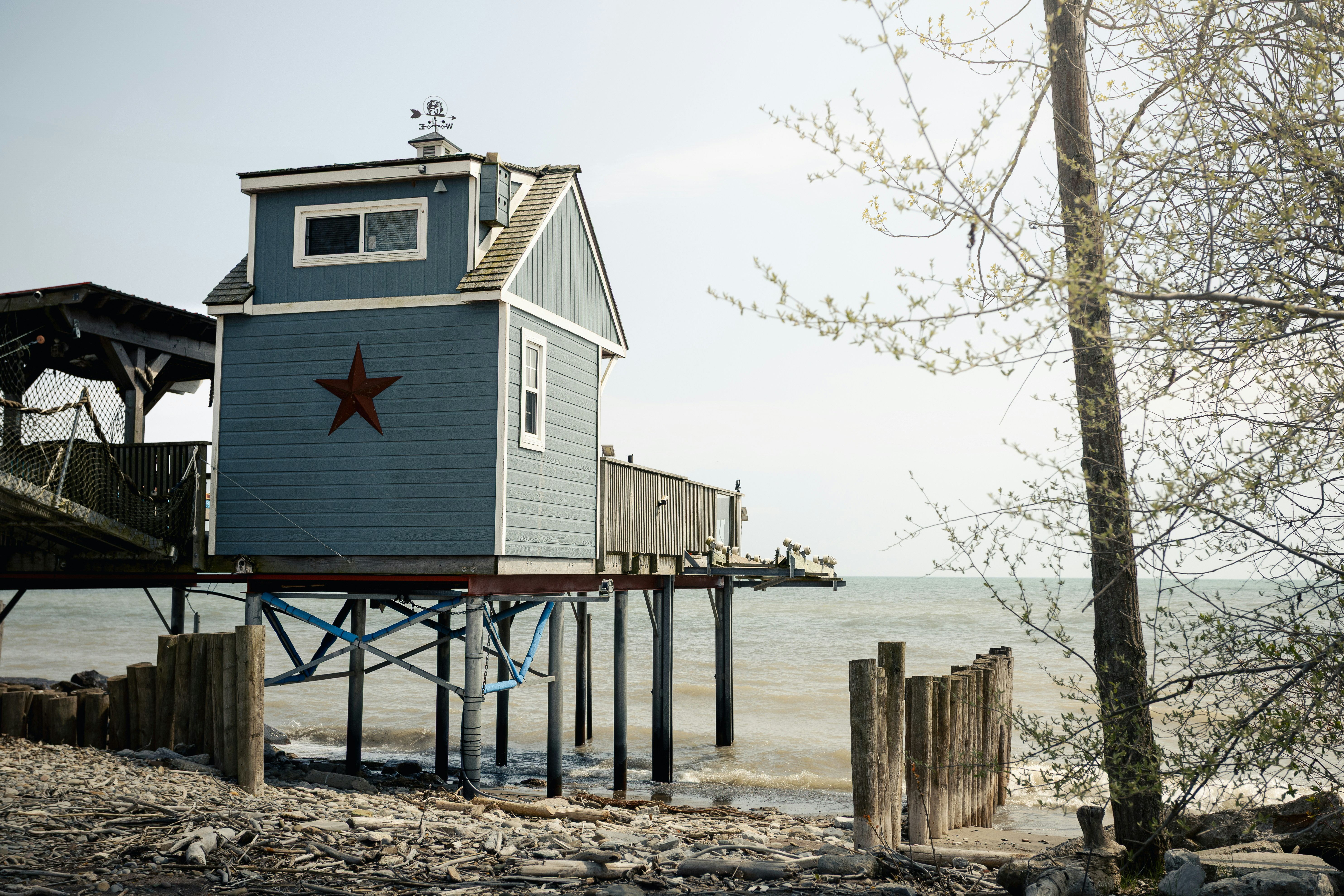 Blue Coastal Cabin on Stilts with Red Star Over the Quiet Sea