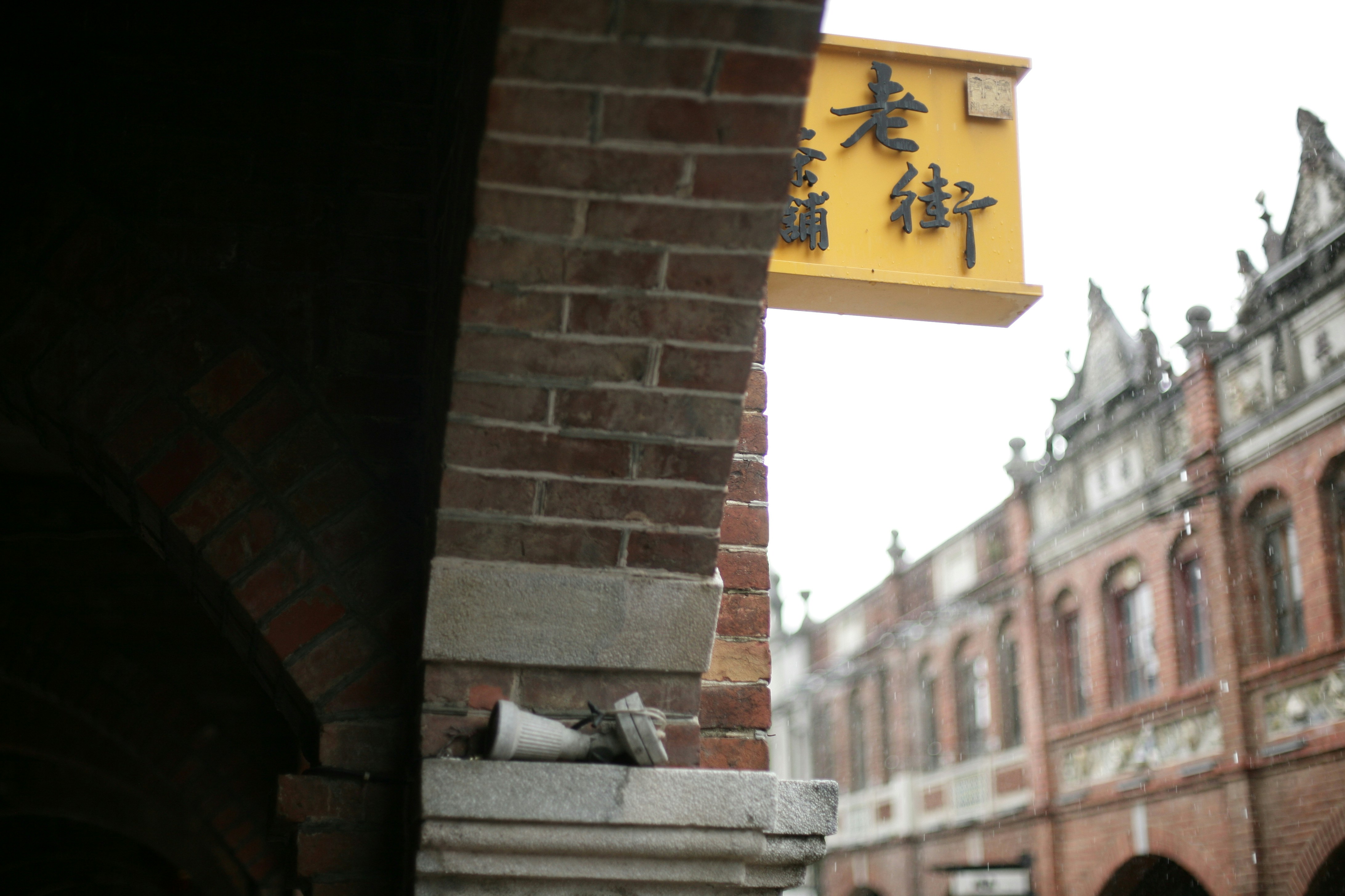 Amber Sign Over a Weathered Brick Arcade Framing an Arched Street