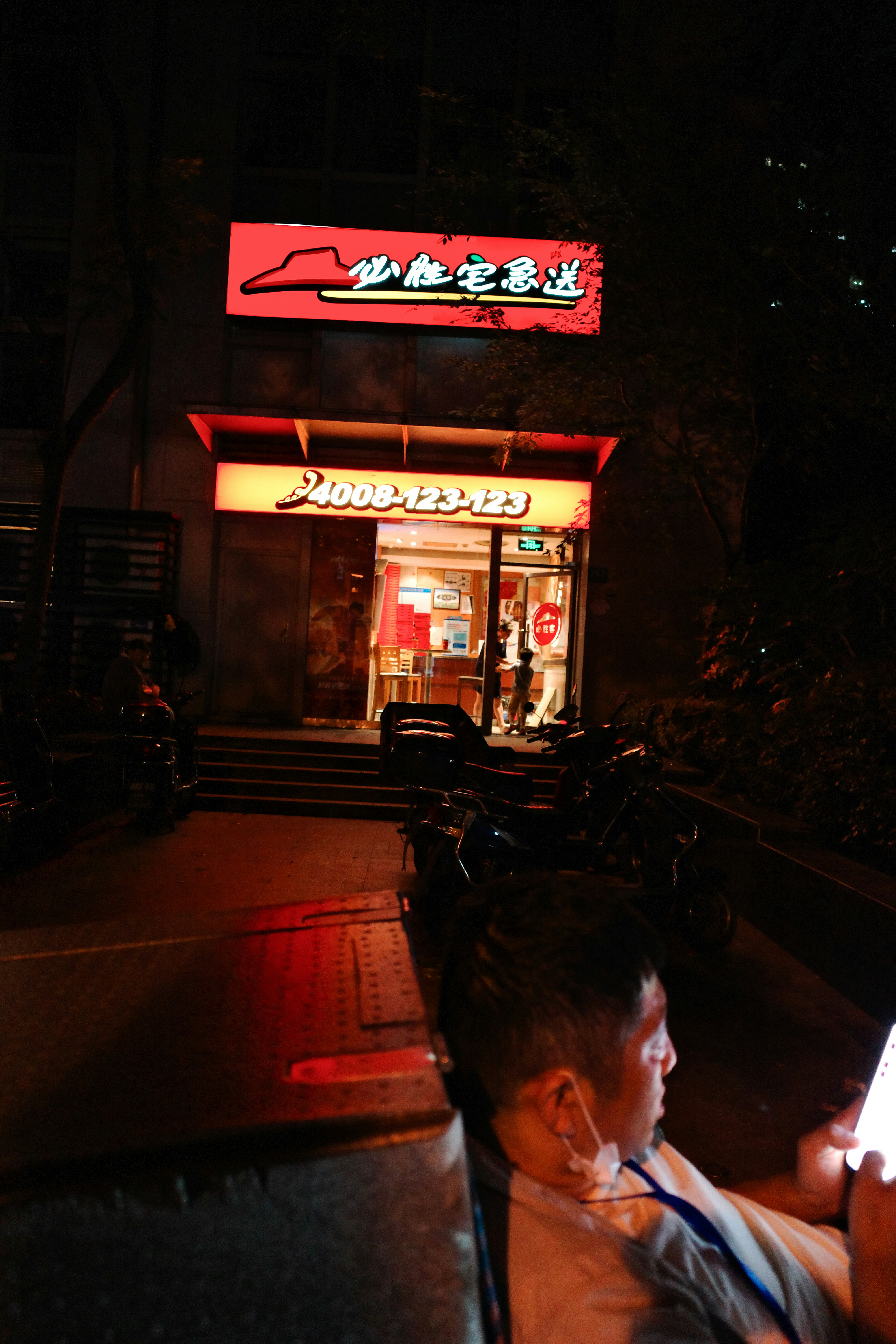 Neon Entrance: Nighttime Street Scene with a Reading Man
