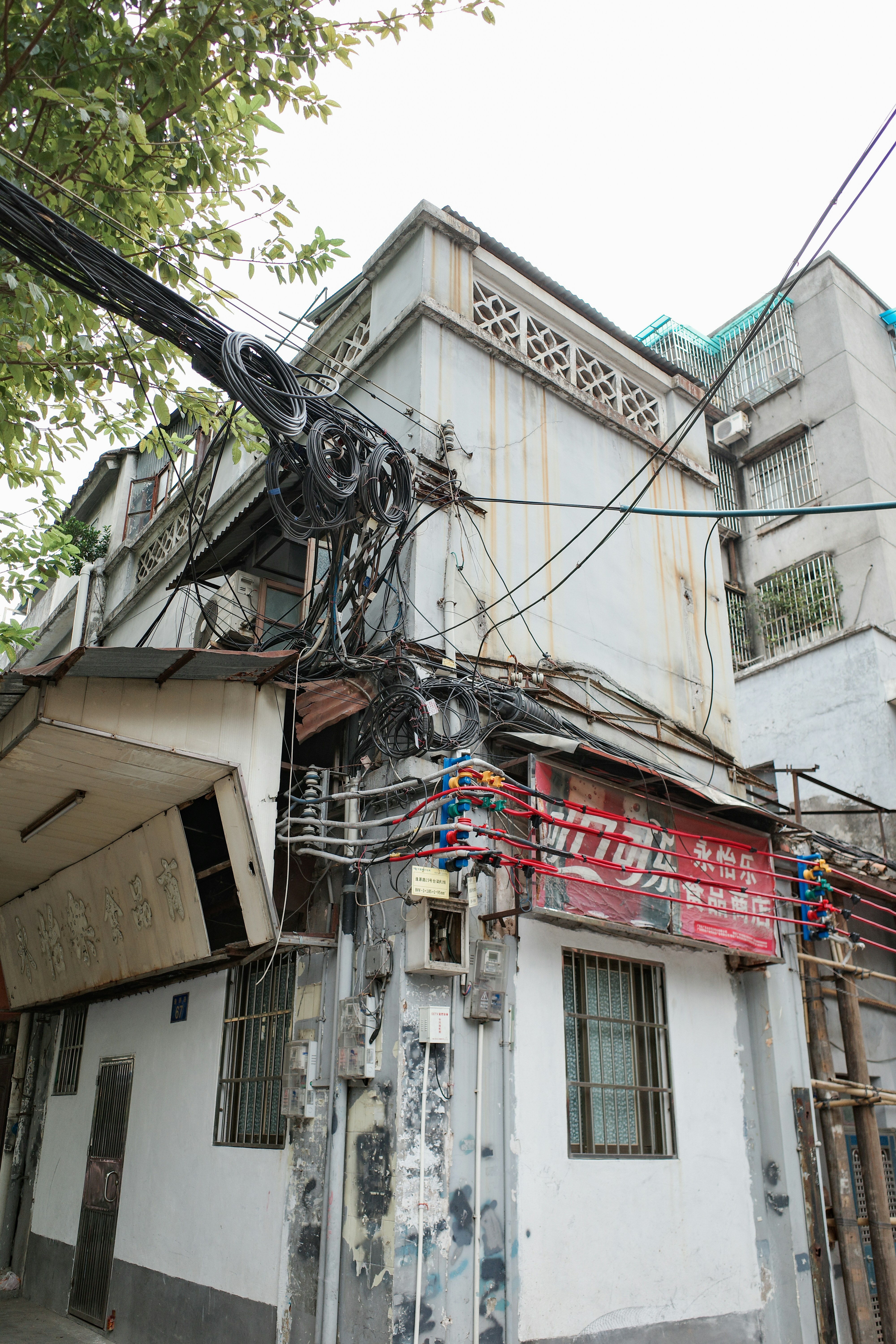 Overhead wires clutter a weathered building's corner. photo – Free ...