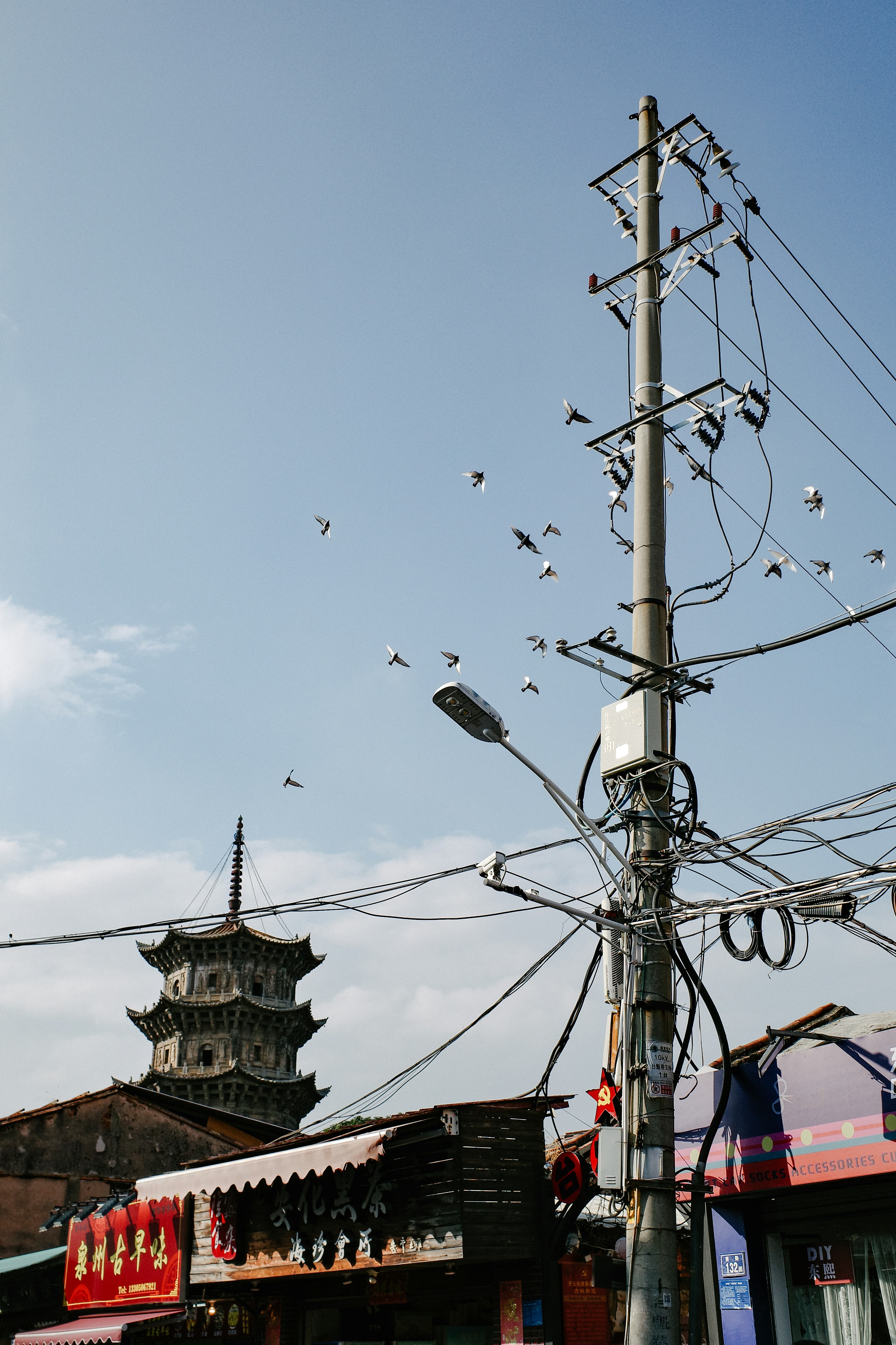 Power Lines and Pagoda: A Skyward Shuffle Above a Bustling Street