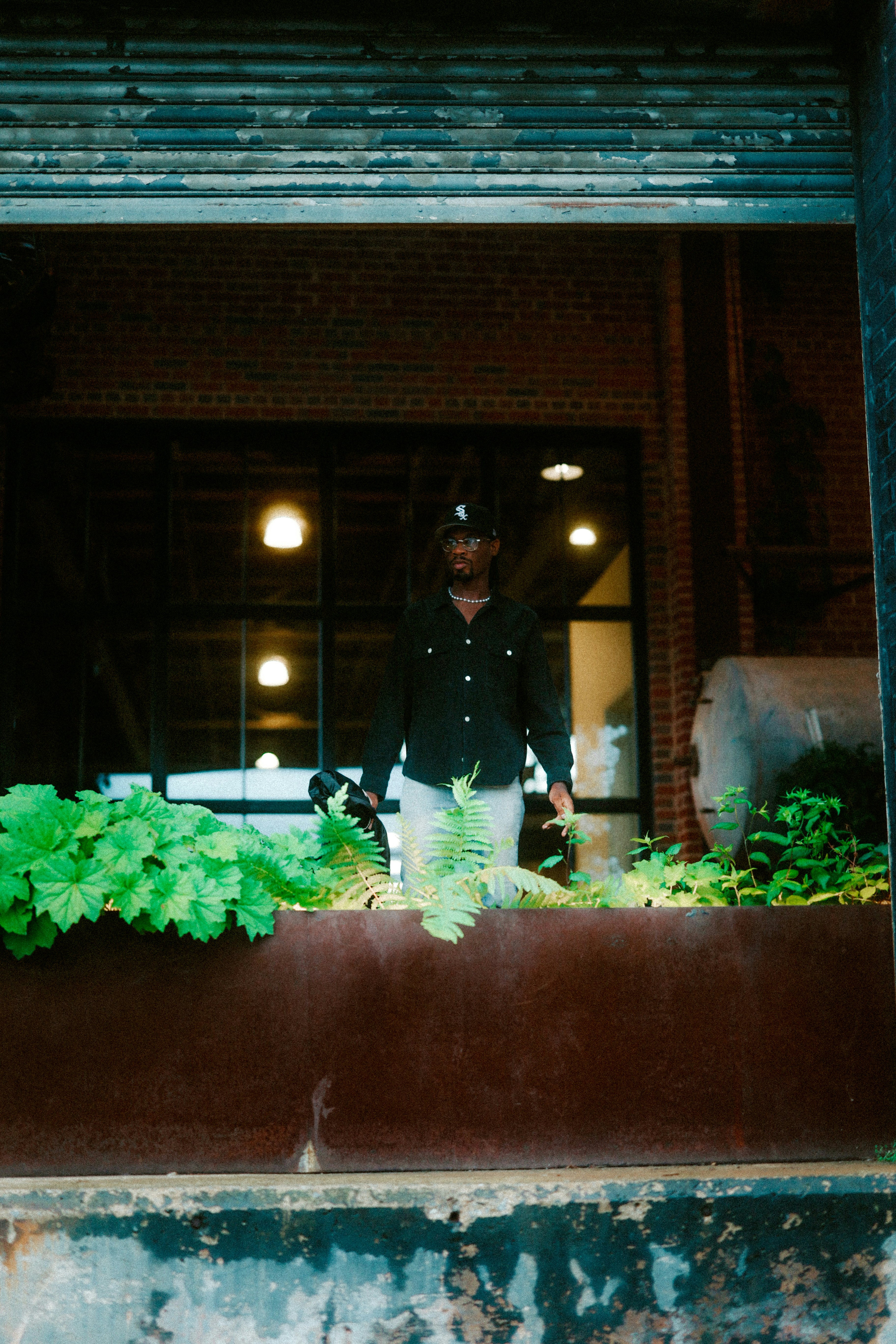 Threshold Portrait: Quiet Authority Amid Brick, Steel, and Green