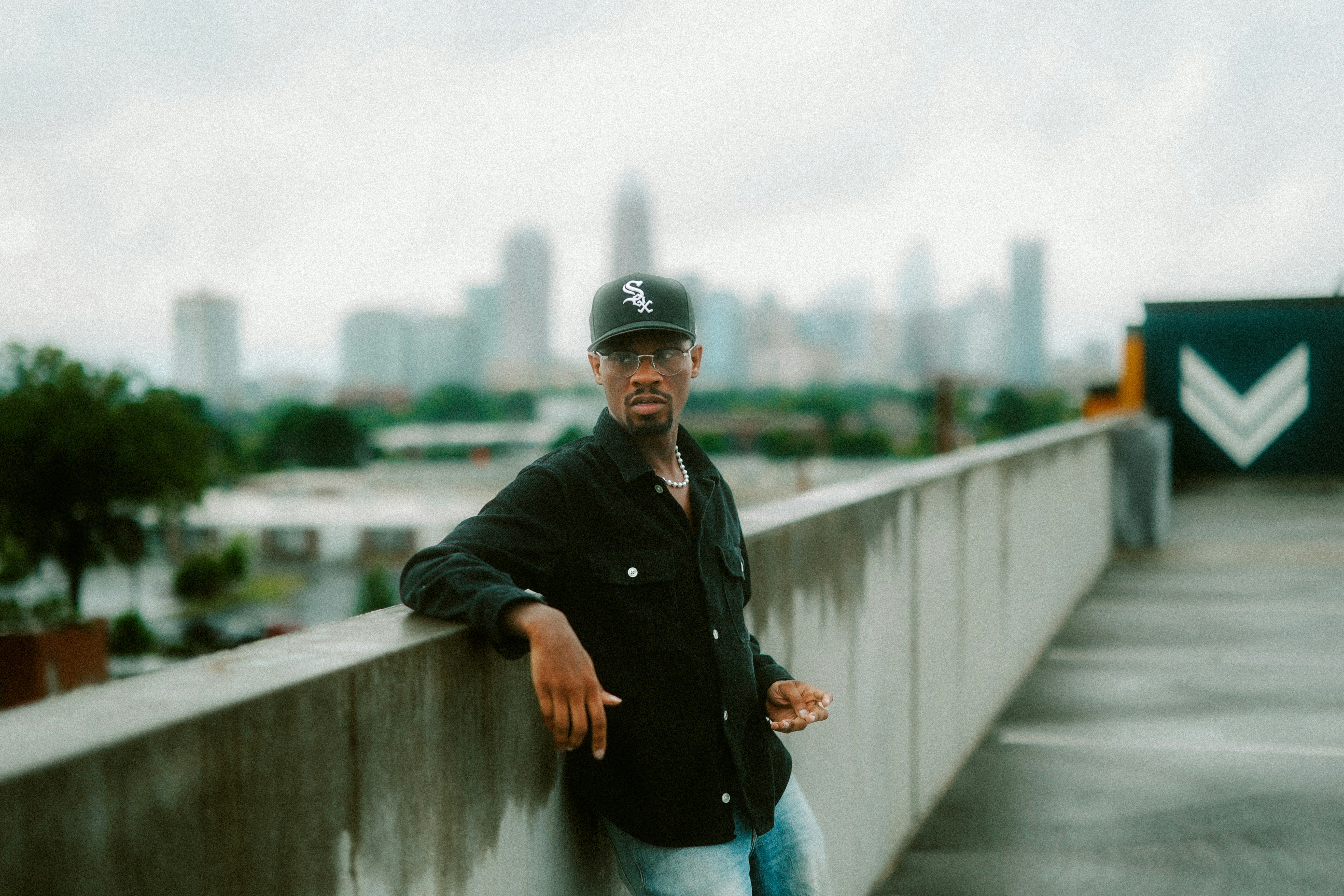 Man poses on a rooftop with city in background. photo – Free Image on ...