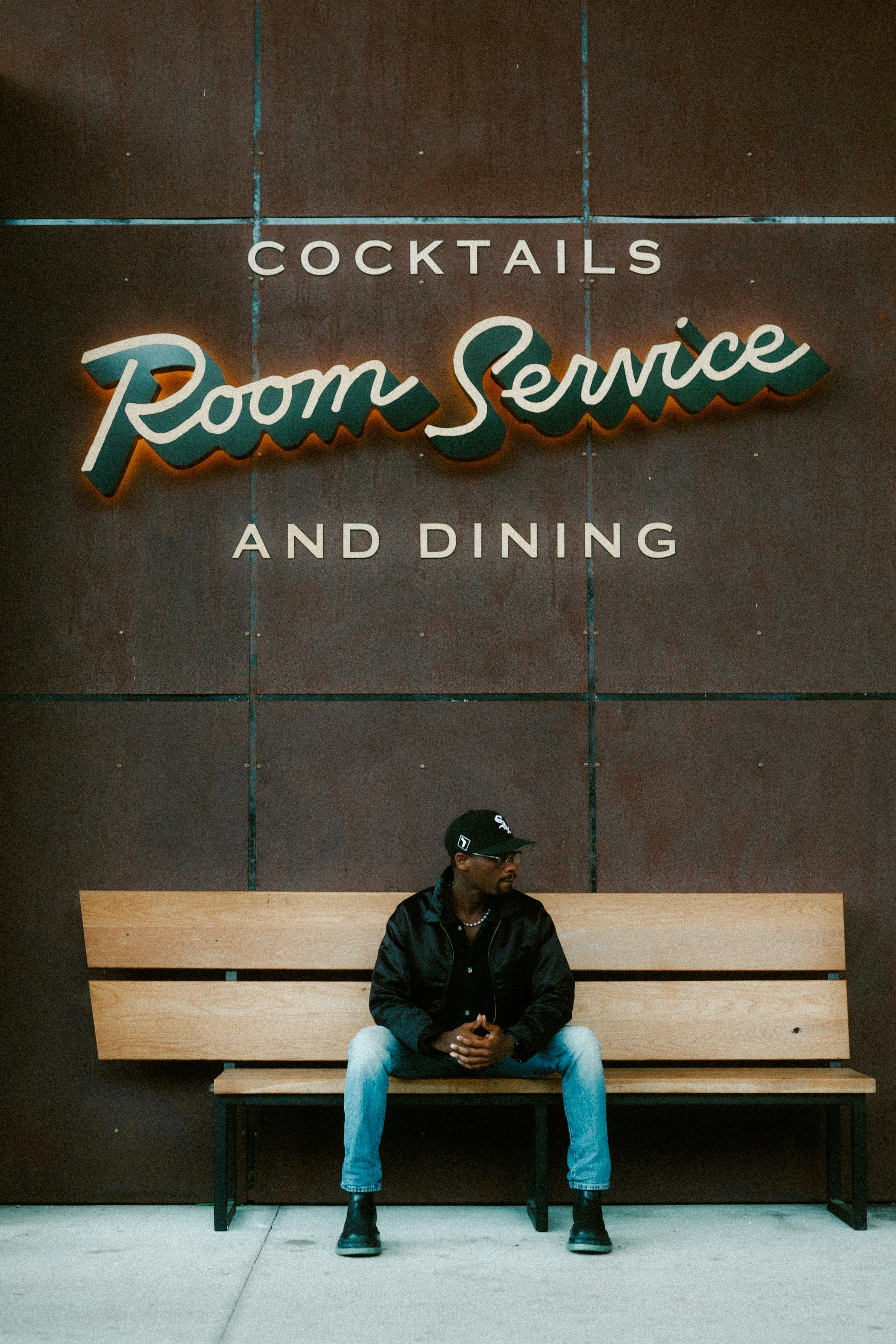 A man sits beneath a "room service" sign. photo – Free Portrait Image ...