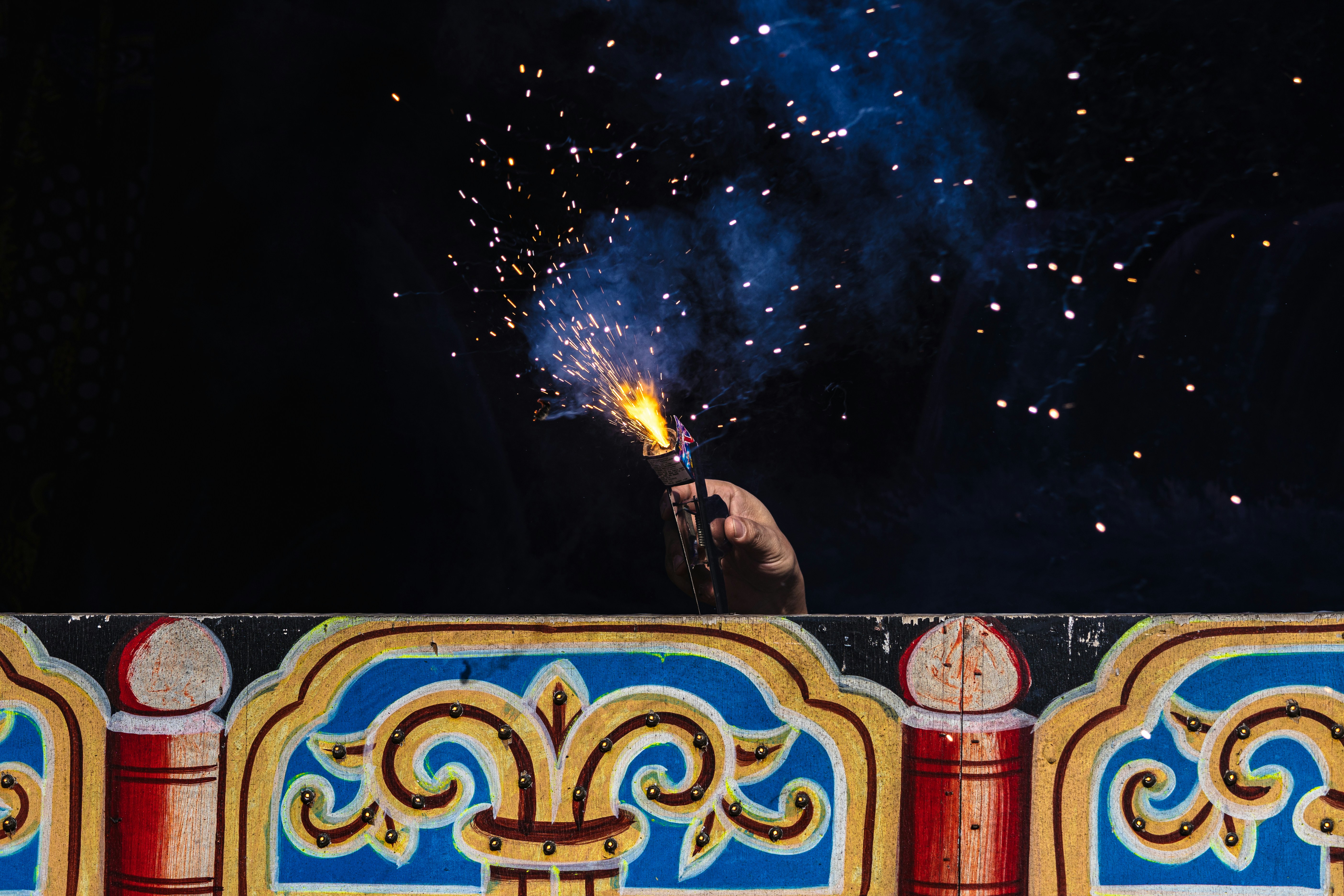 Spark of Fire: Handheld Firework Over a Carousel Crest