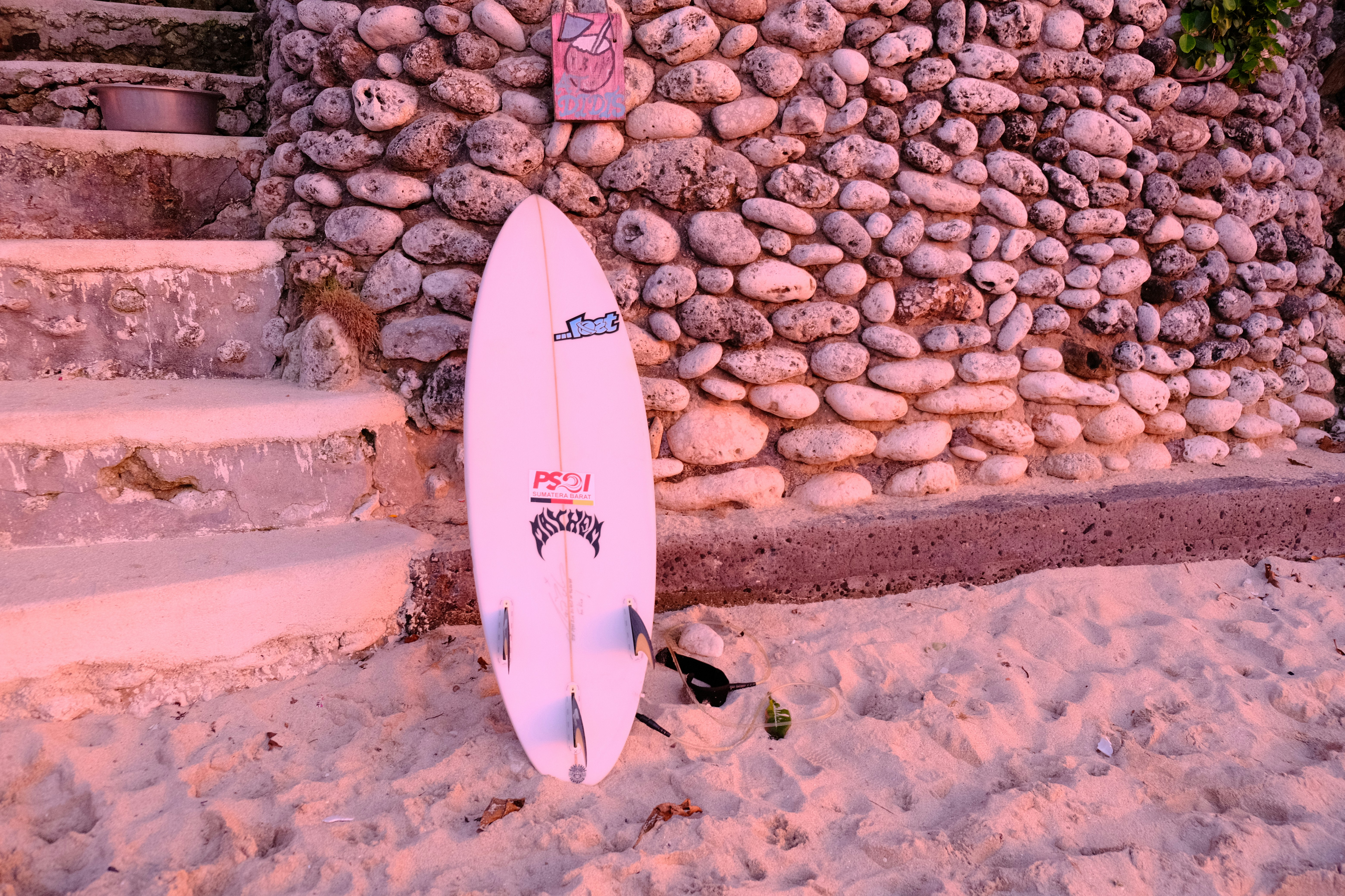 Pink-Glow Surfboard by a Pebble Wall