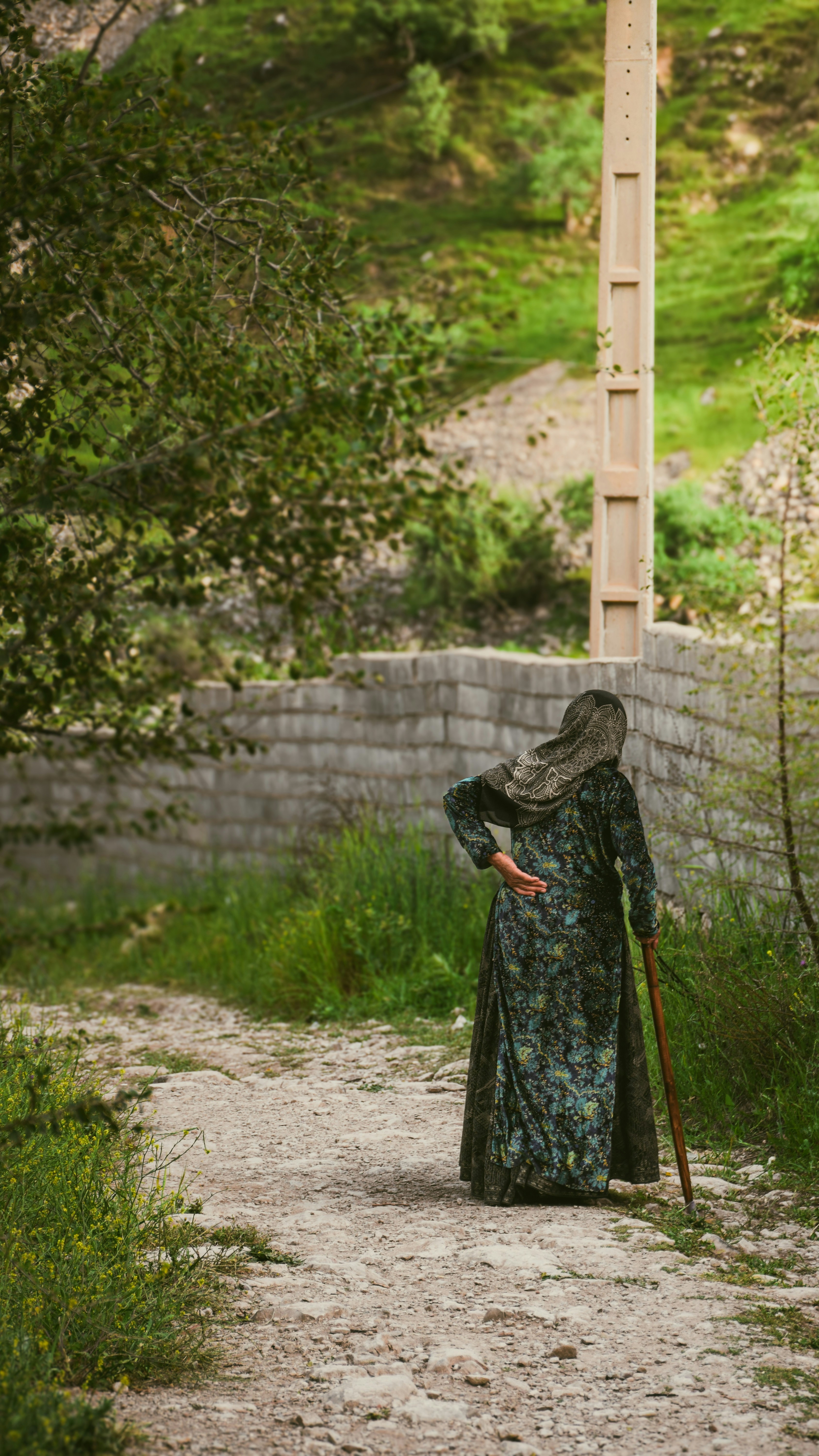 The Quiet Wanderer by the Stone Wall: A Floral-Dress Portrait on a Rural Path