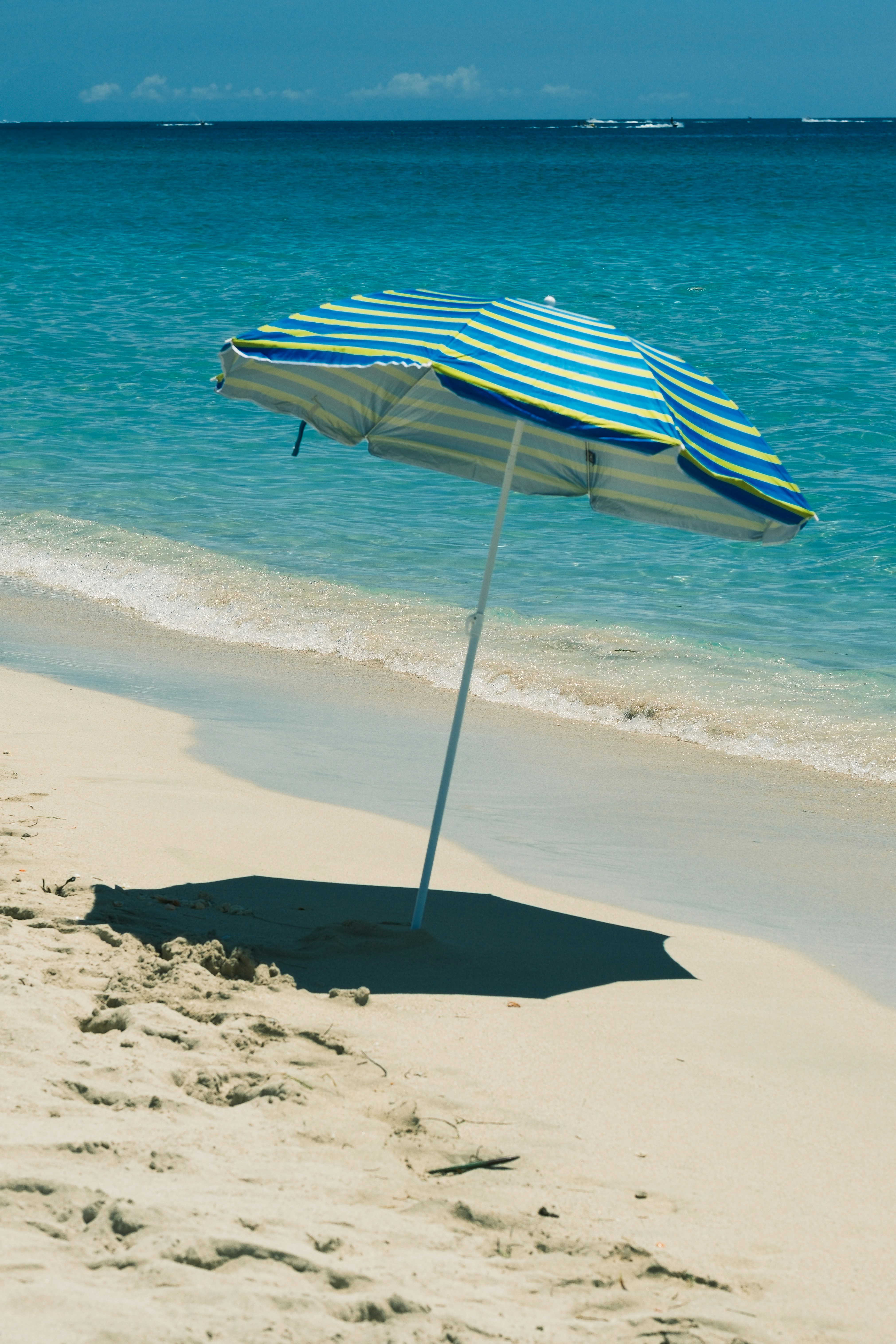 Stripe-Backed Shade: A Lone Beach Umbrella in Turquoise Quiet