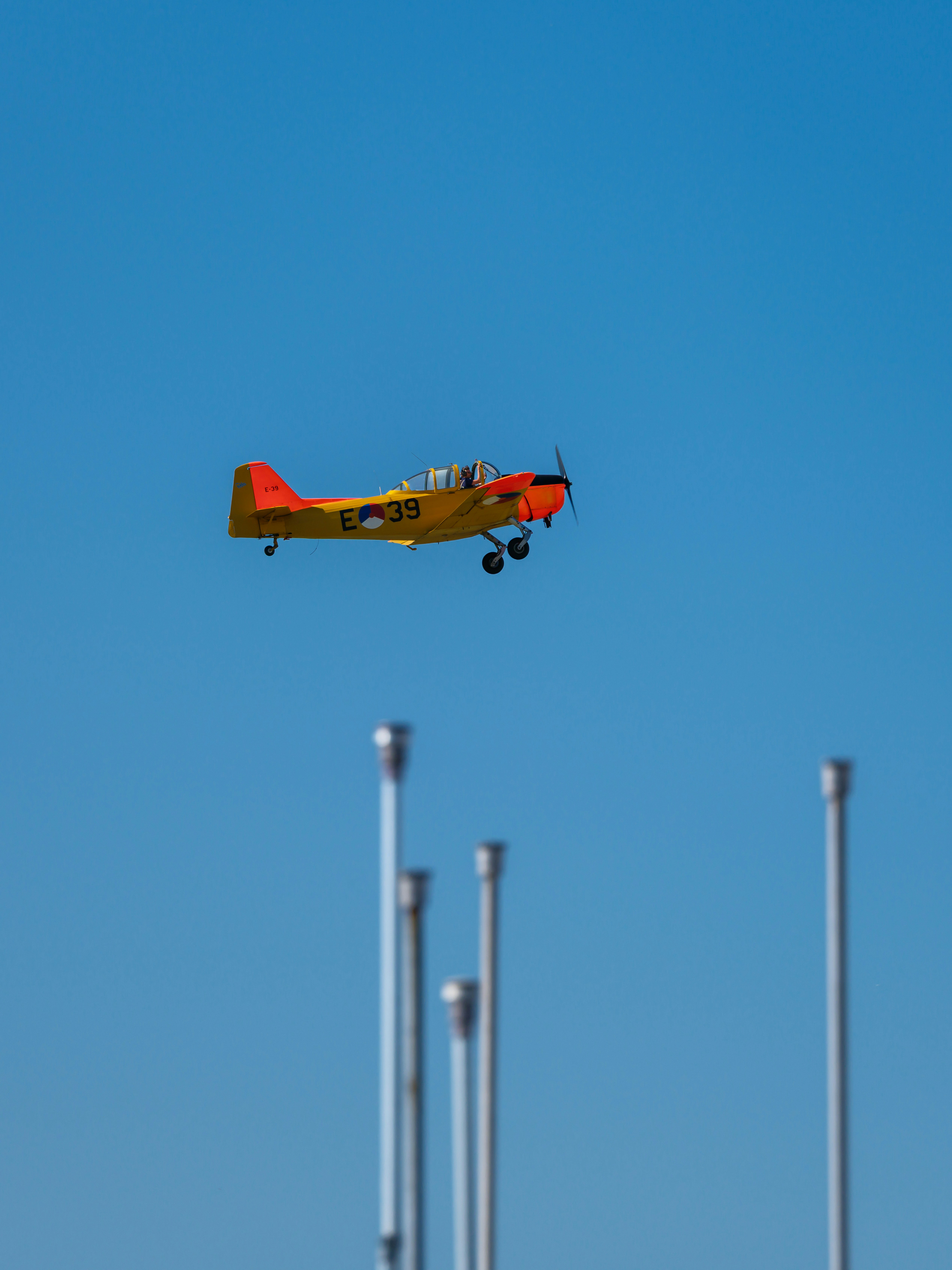Yellow Cub aircraft in blue sky above outboard runway pylons