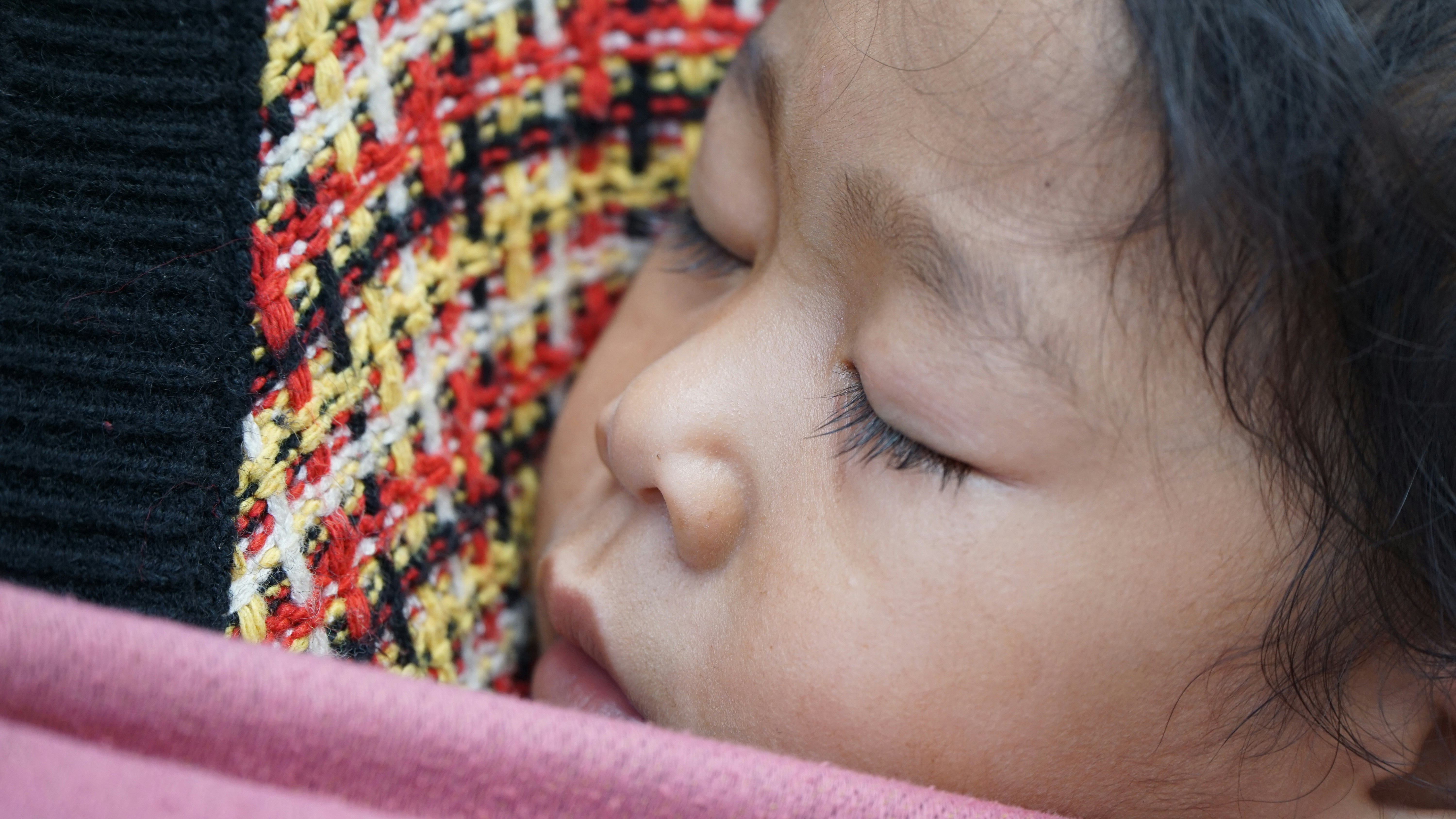 Soft Slumber: Close-Up of a Sleeping Child Nestled in Colorful Knit