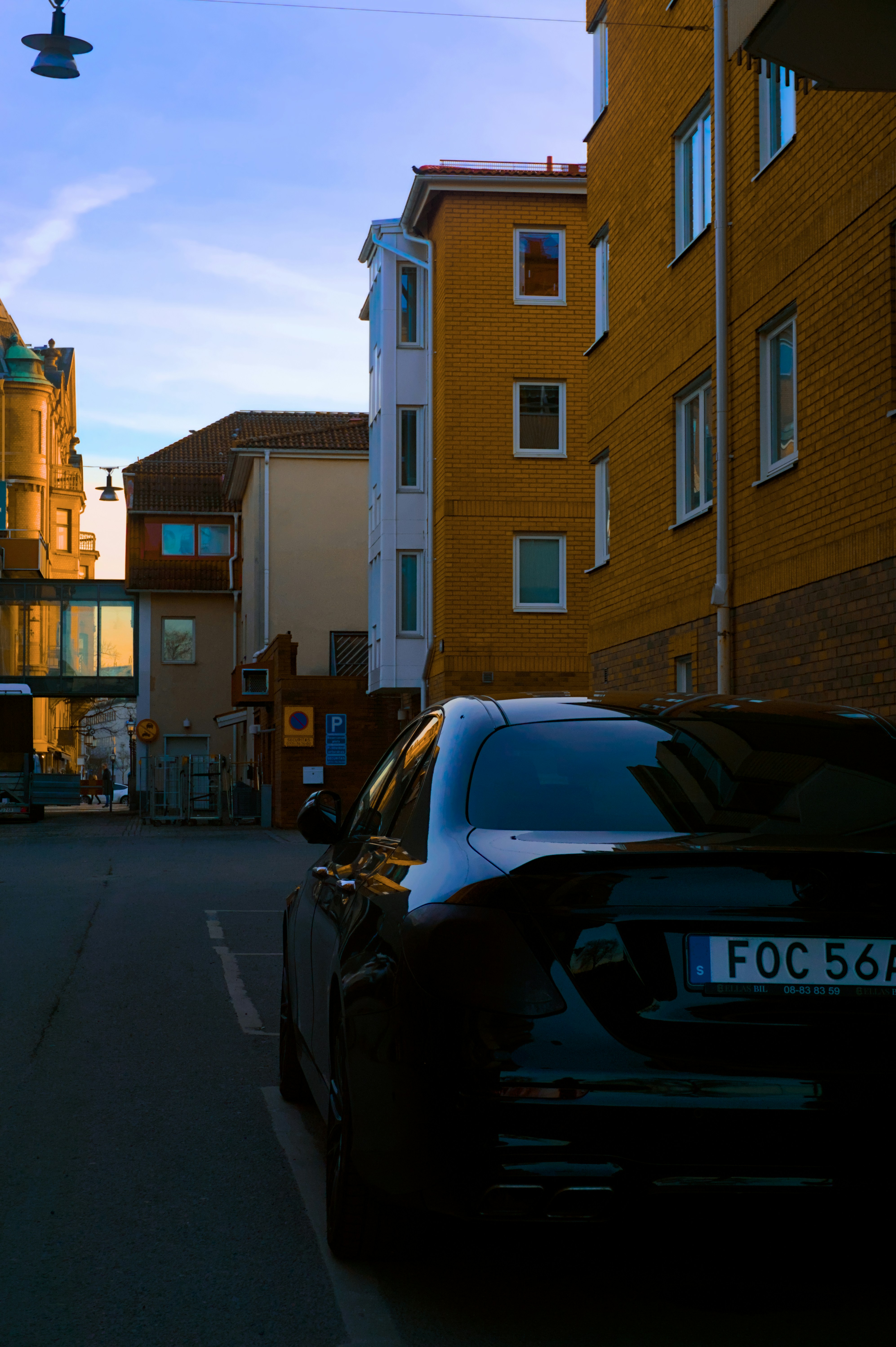 Sunlit Narrow Street: A Black Sedan Anchors a Brick-Walled Block