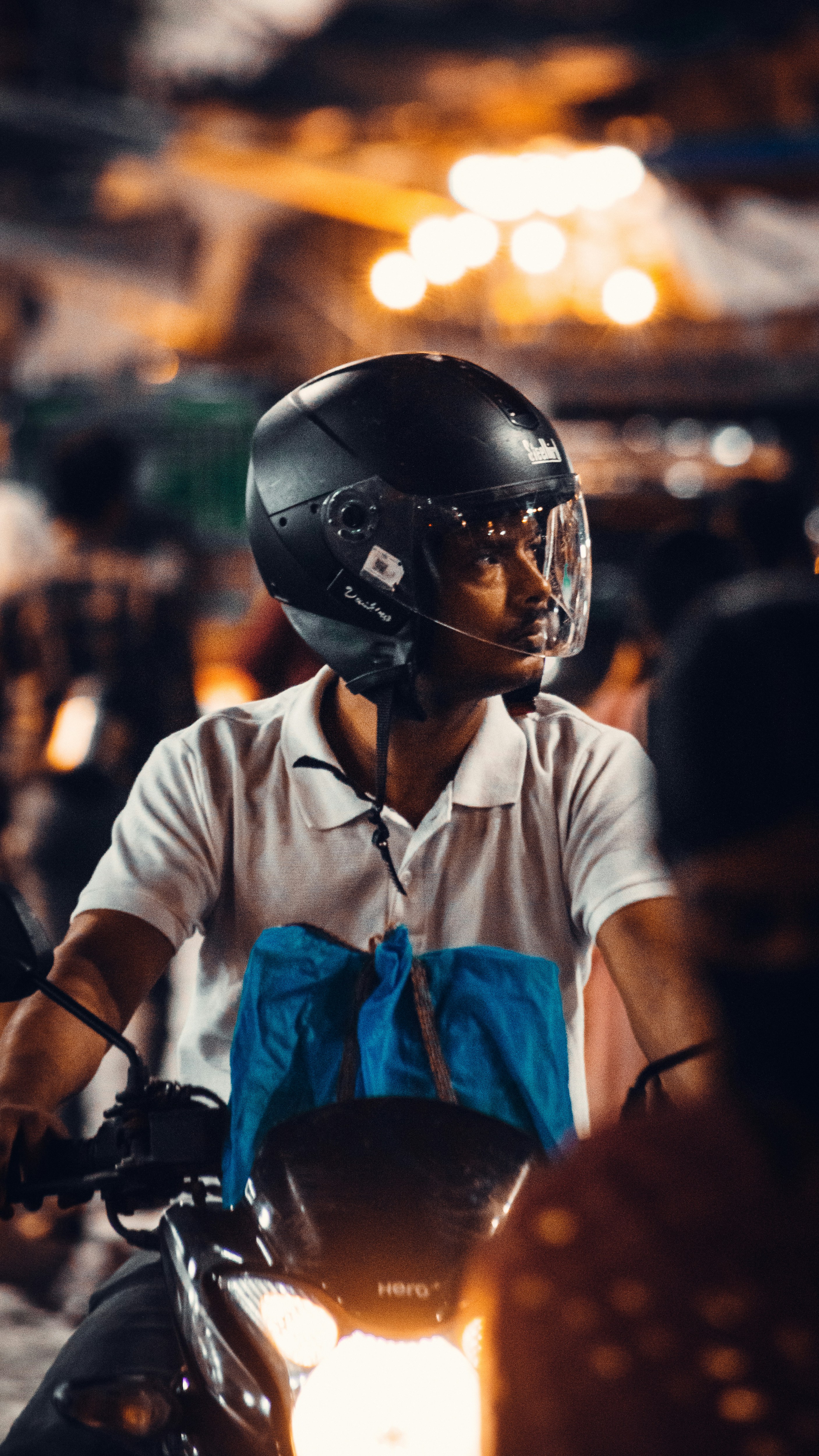 Neon-Bokeh Rider: Helmeted Figure Amid Night Market Lights