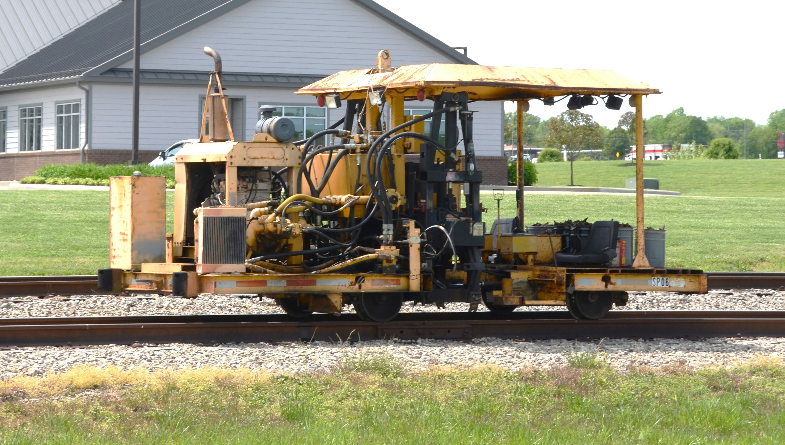 Yellow Rail Maintenance Machine Resting Beside a Modern Facility