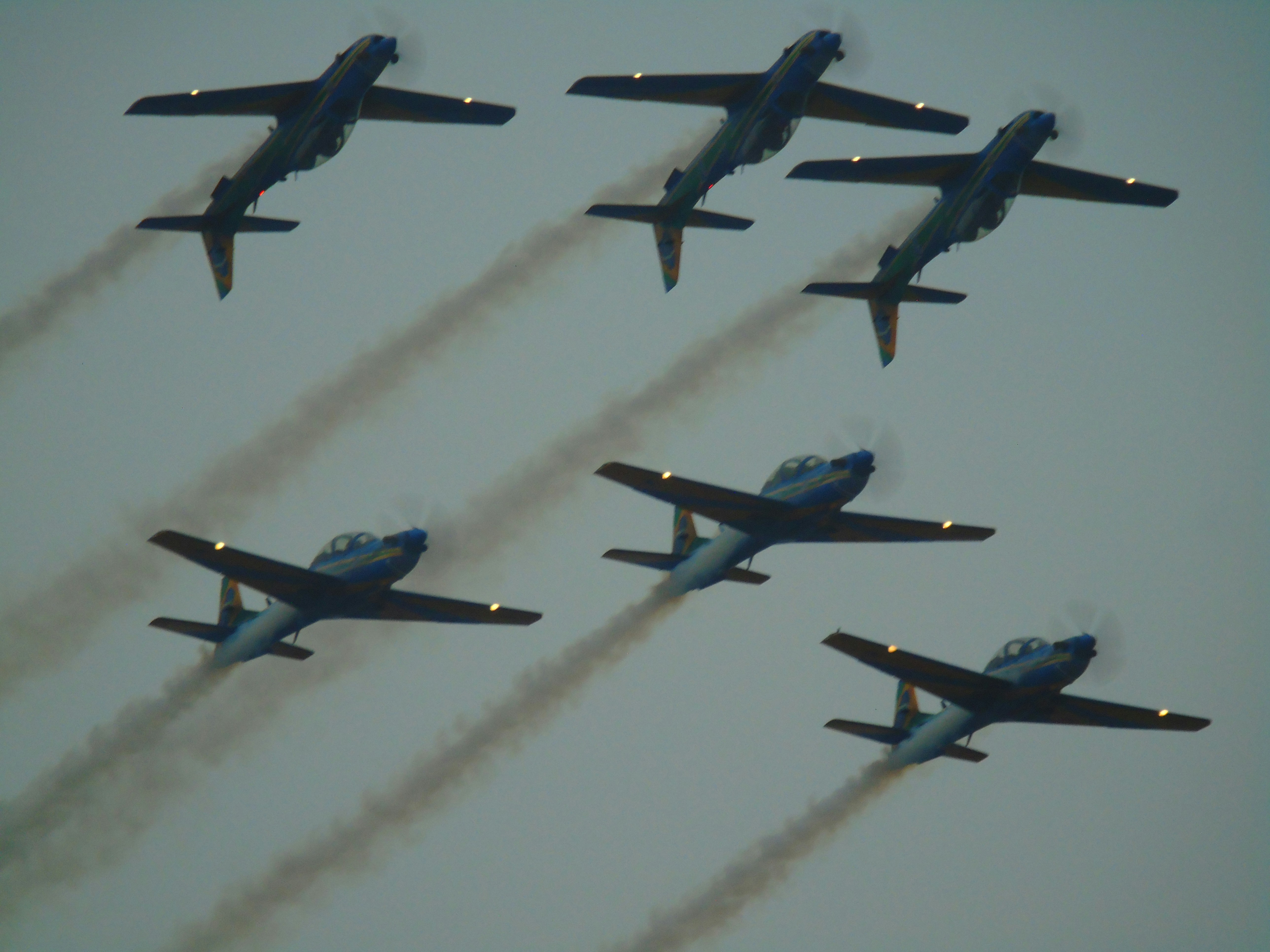 Six airplanes fly in formation, leaving smoke trails.