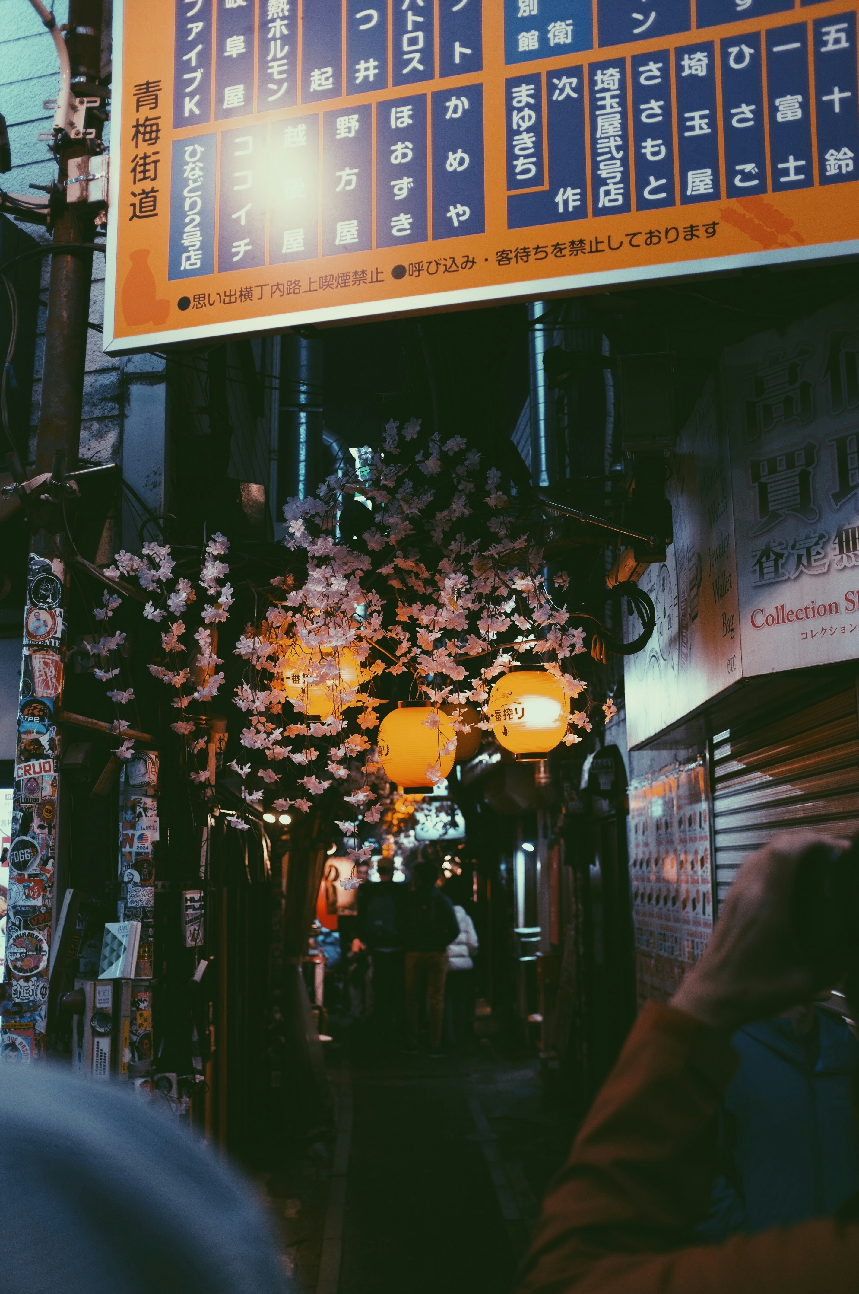 A dark alleyway lit by lanterns and signs.