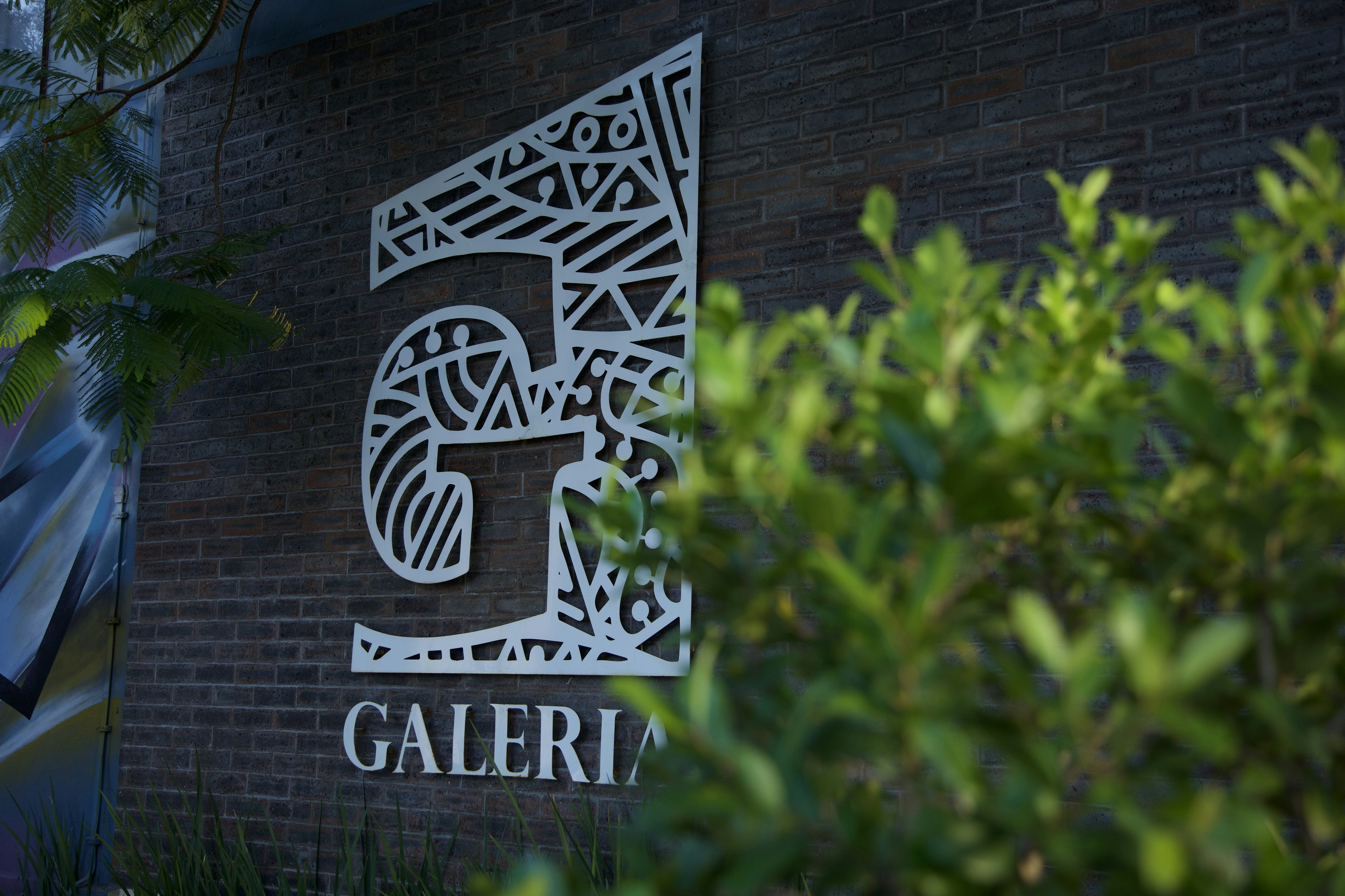 Ornate G Logo on Brick Gallery Wall Framed by Greenery