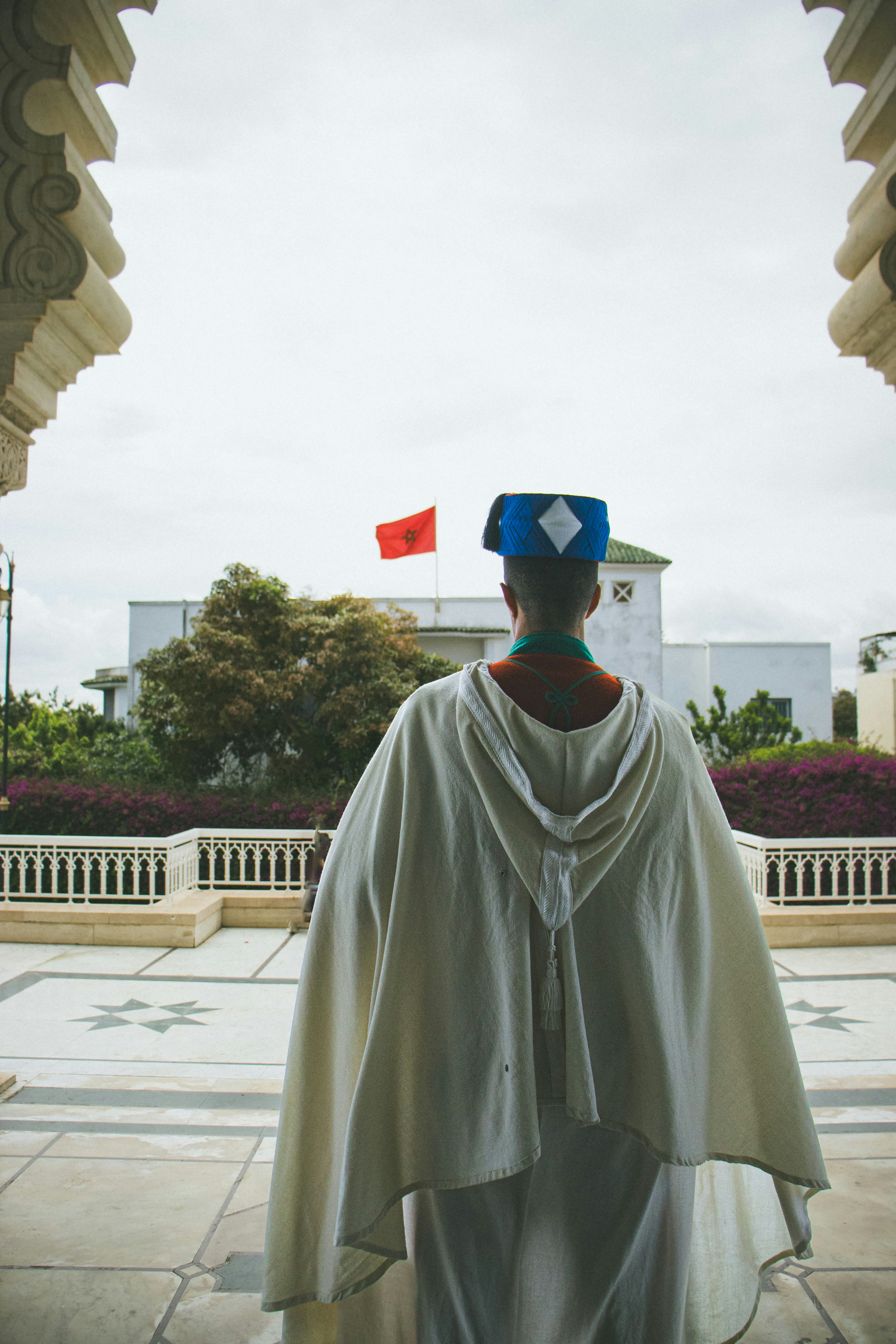 A person in traditional robes stands before a building. photo – Free ...