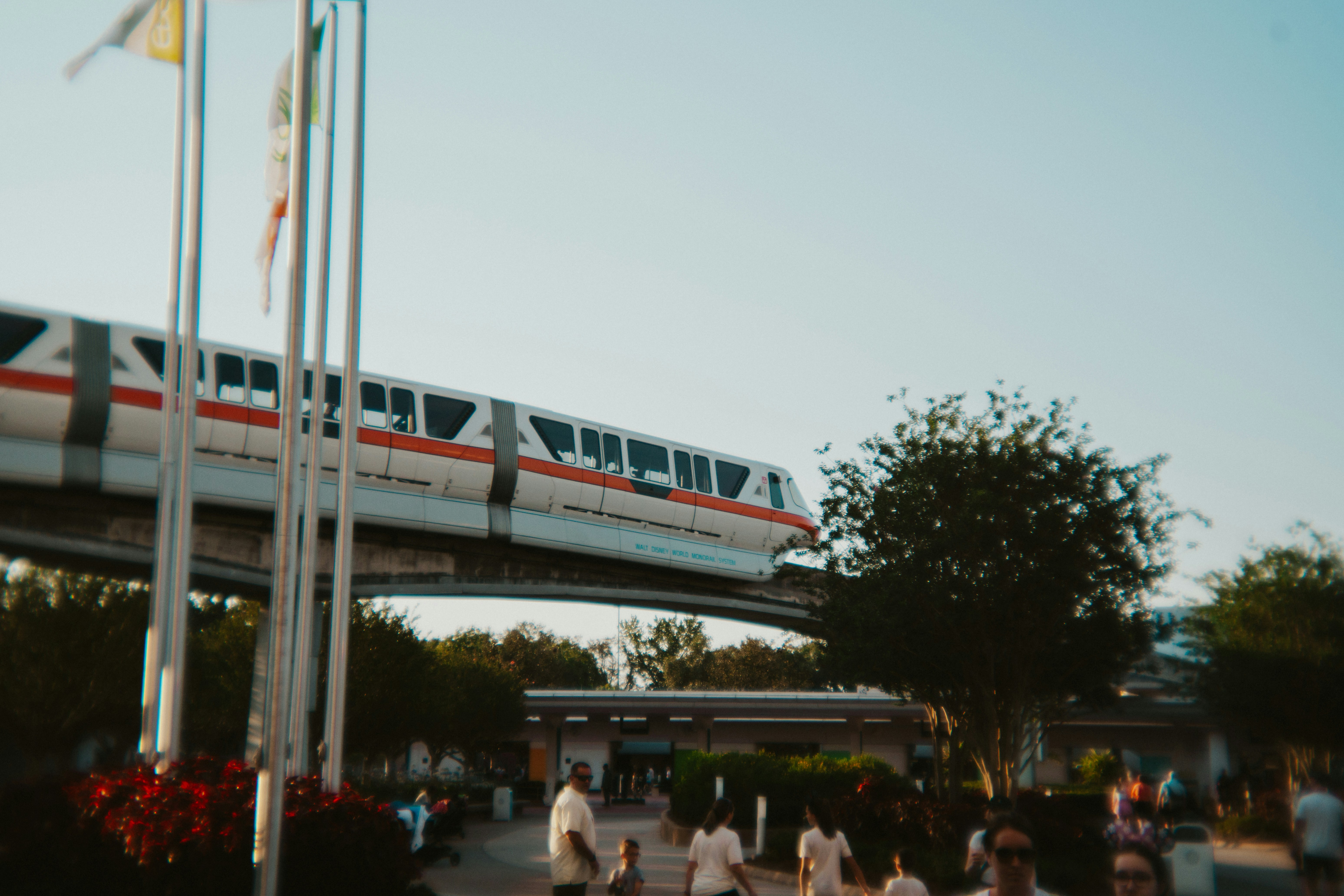 White-Red Monorail Traversing the Sky Over a Lively City Plaza