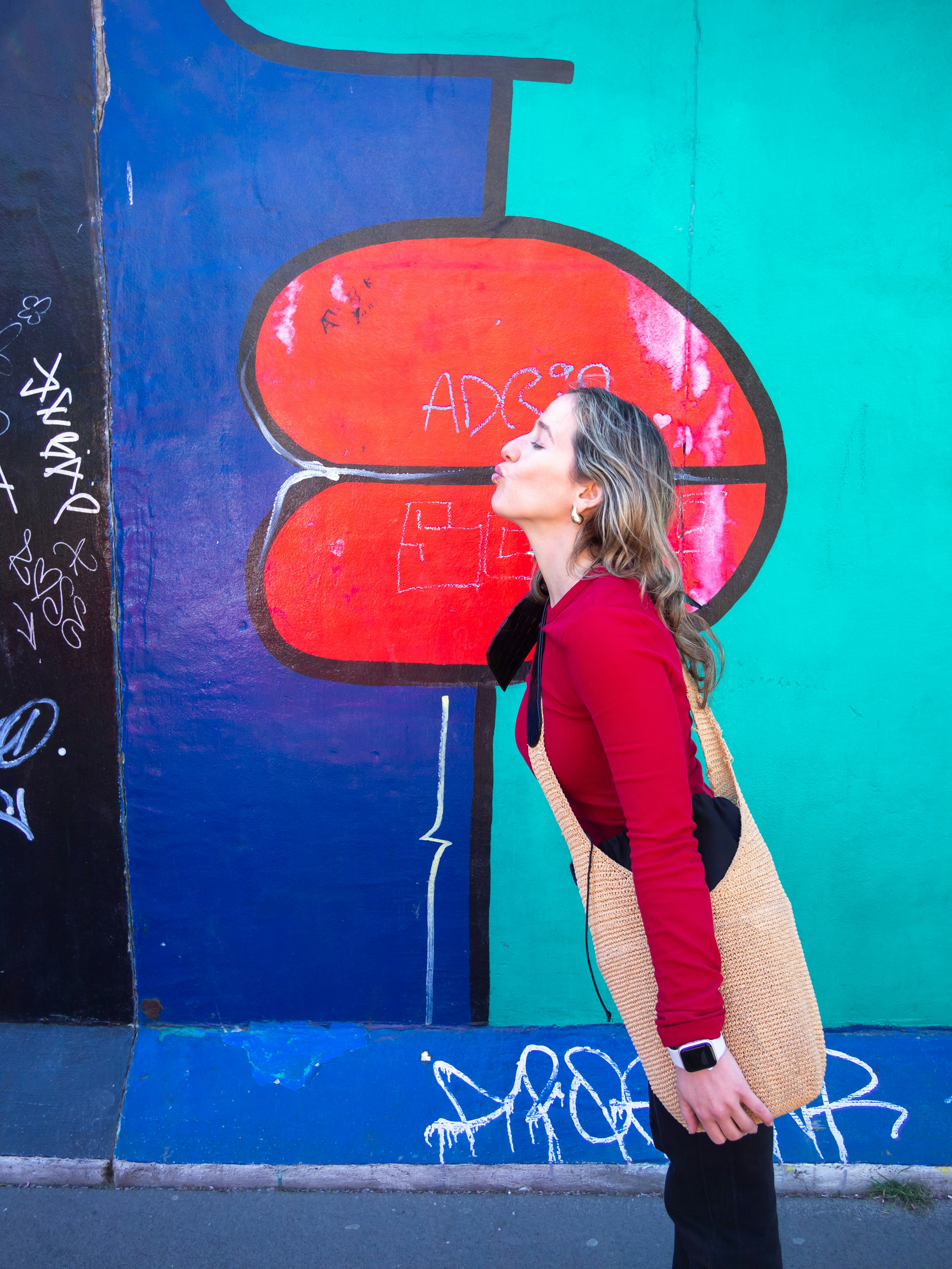 Curved graffiti meets a poised passerby in neon-bright alley