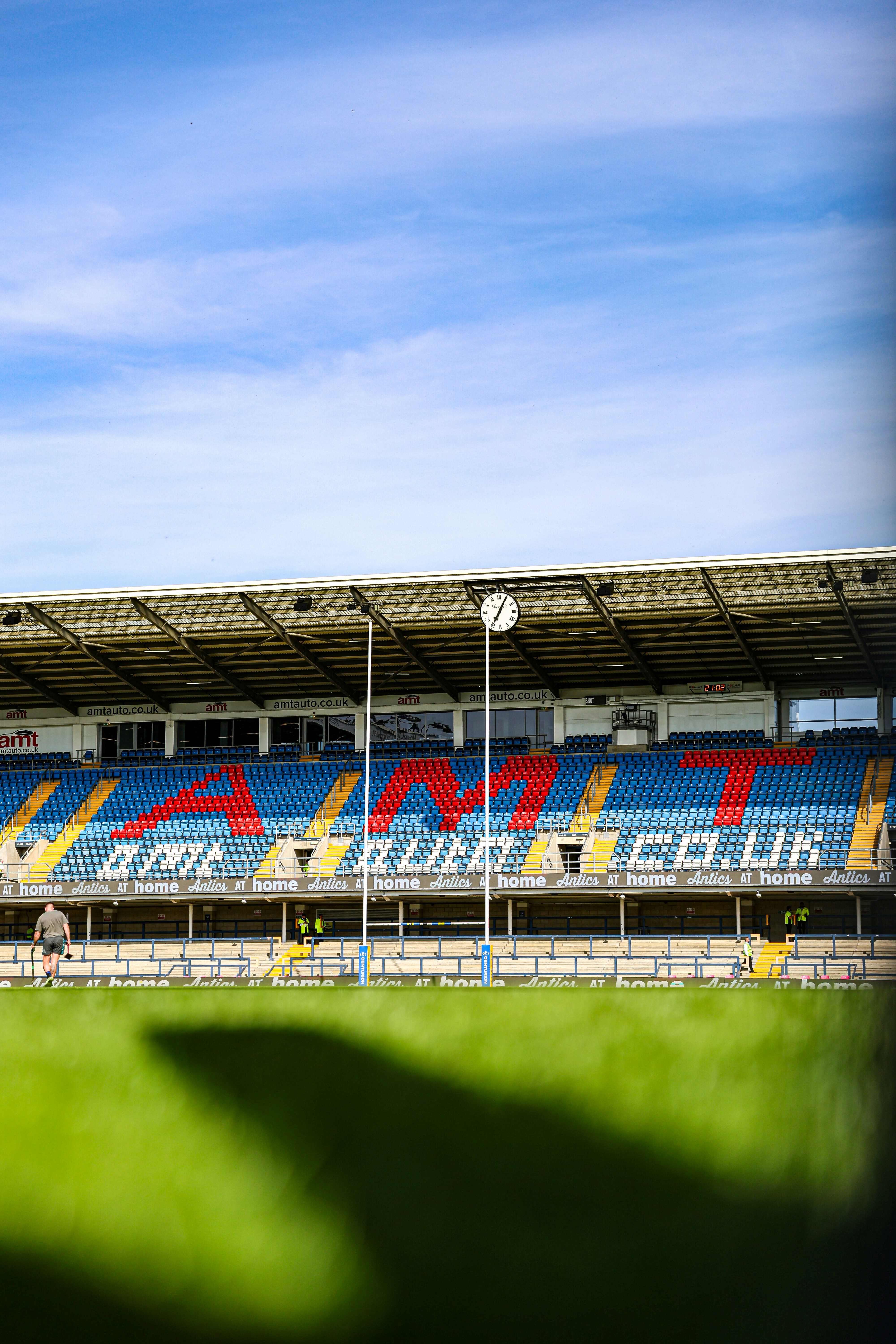 Vibrant letters spelling 'AMIT' adorn the stadium seats, capturing the essence of team pride. A clock hangs above, marking the anticipation of the game.