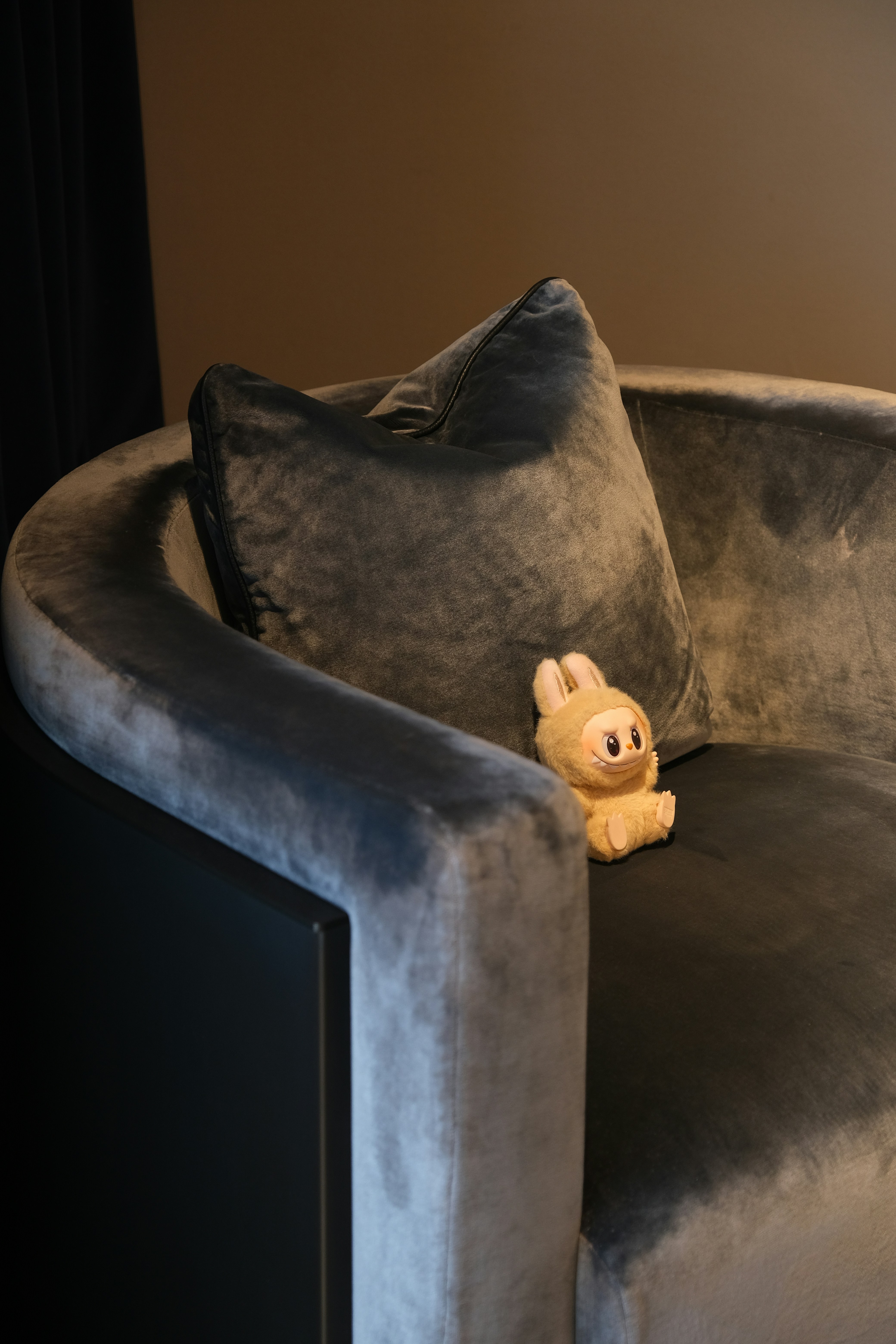 A stuffed bunny sits on a luxurious gray couch. photo – Free Labubu ...