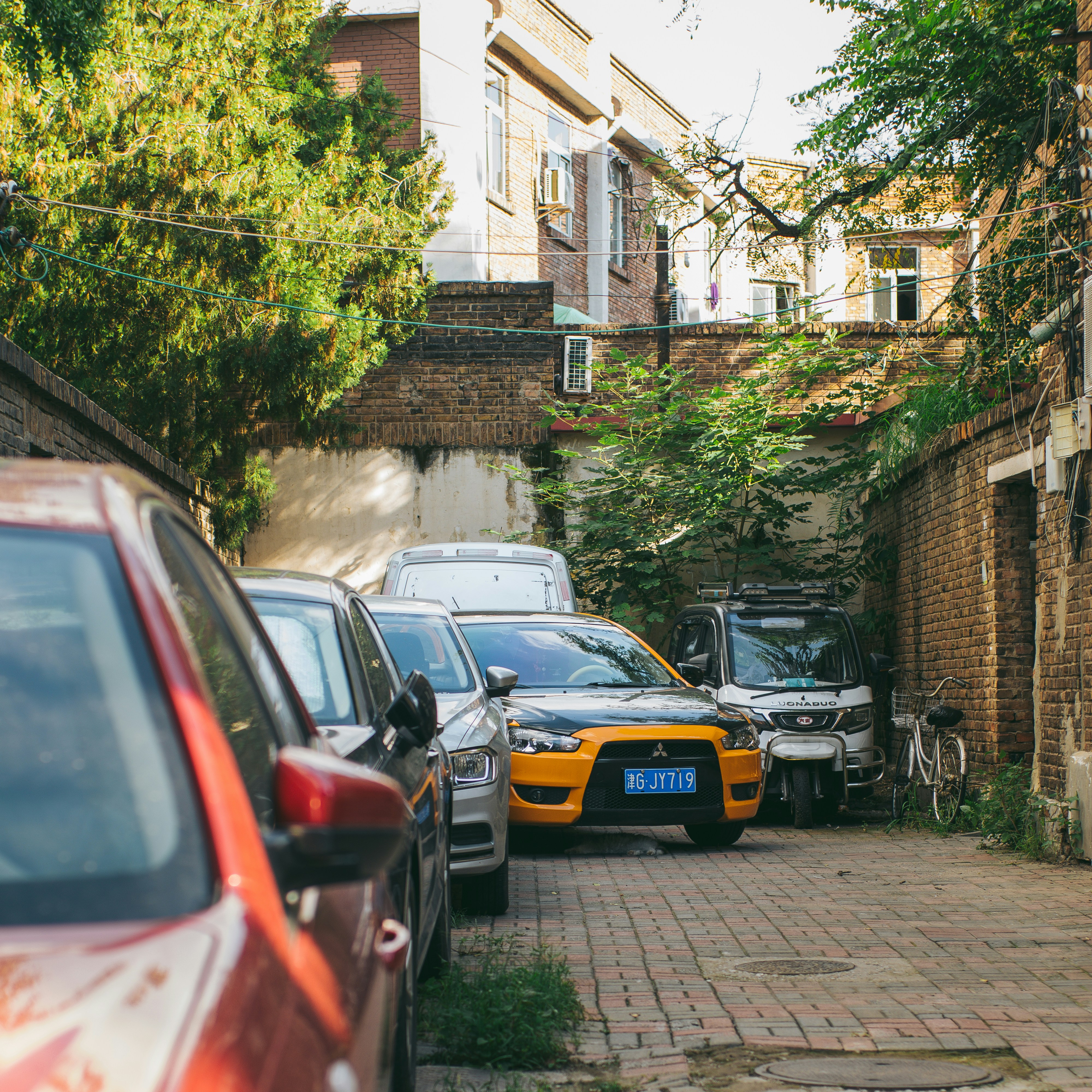 Cars are parked on a brick alleyway.
