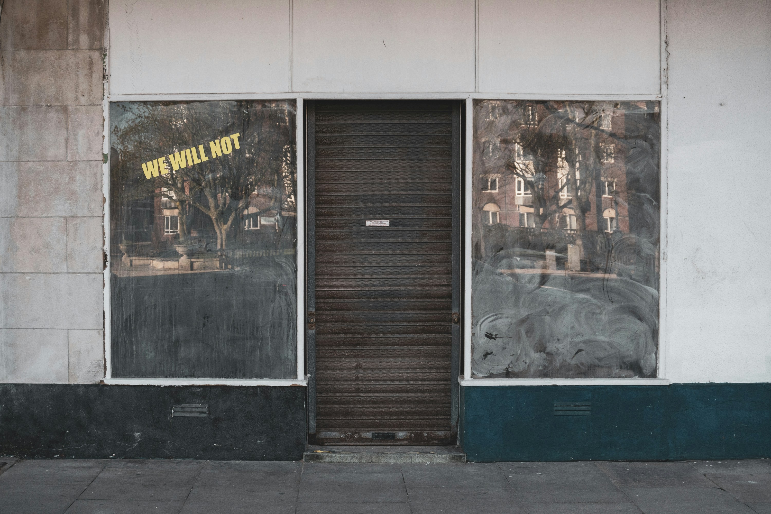 Closed storefront with a "we will not" sign. photo – Free City Image on ...
