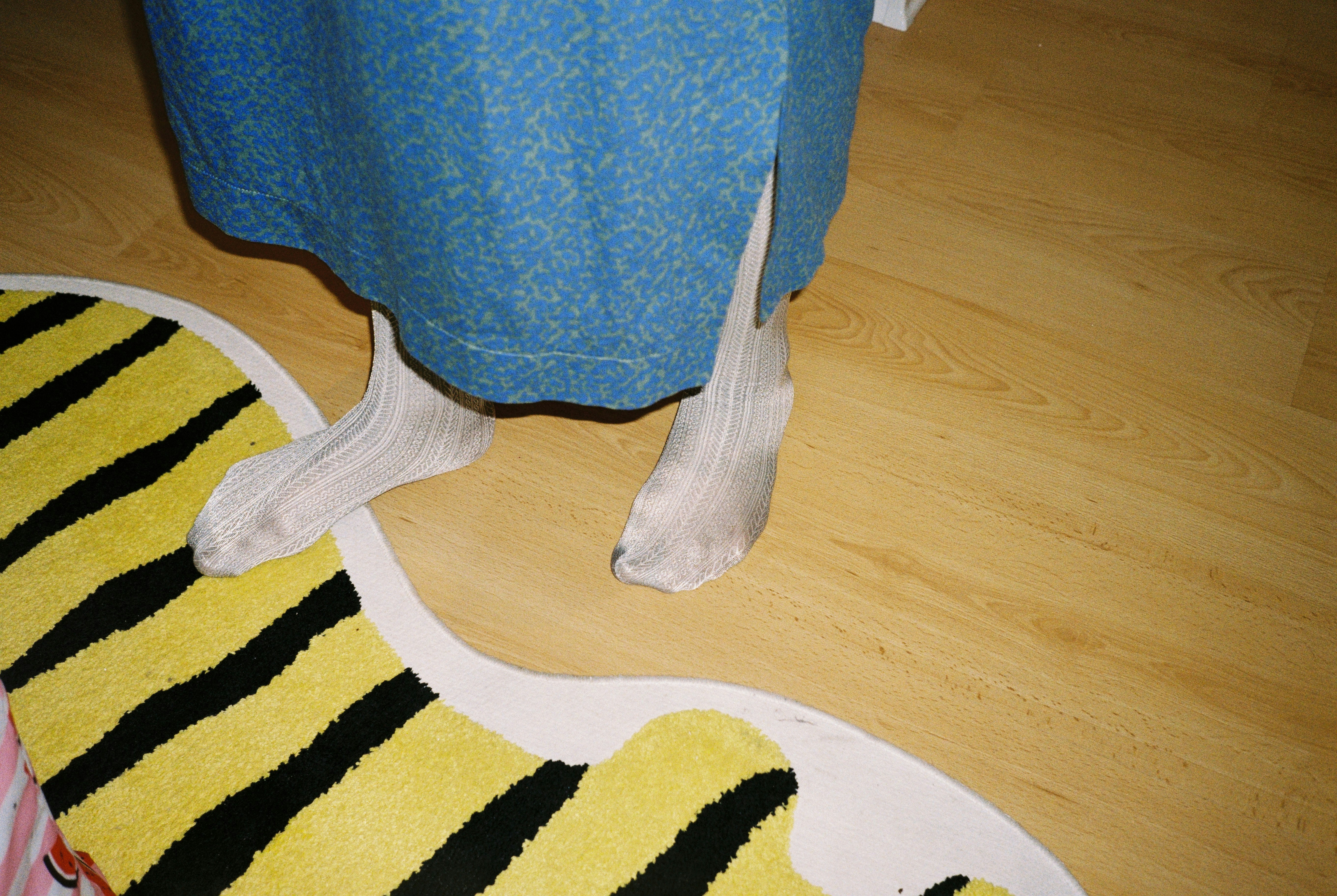 Person's legs and feet are over a colorful rug.