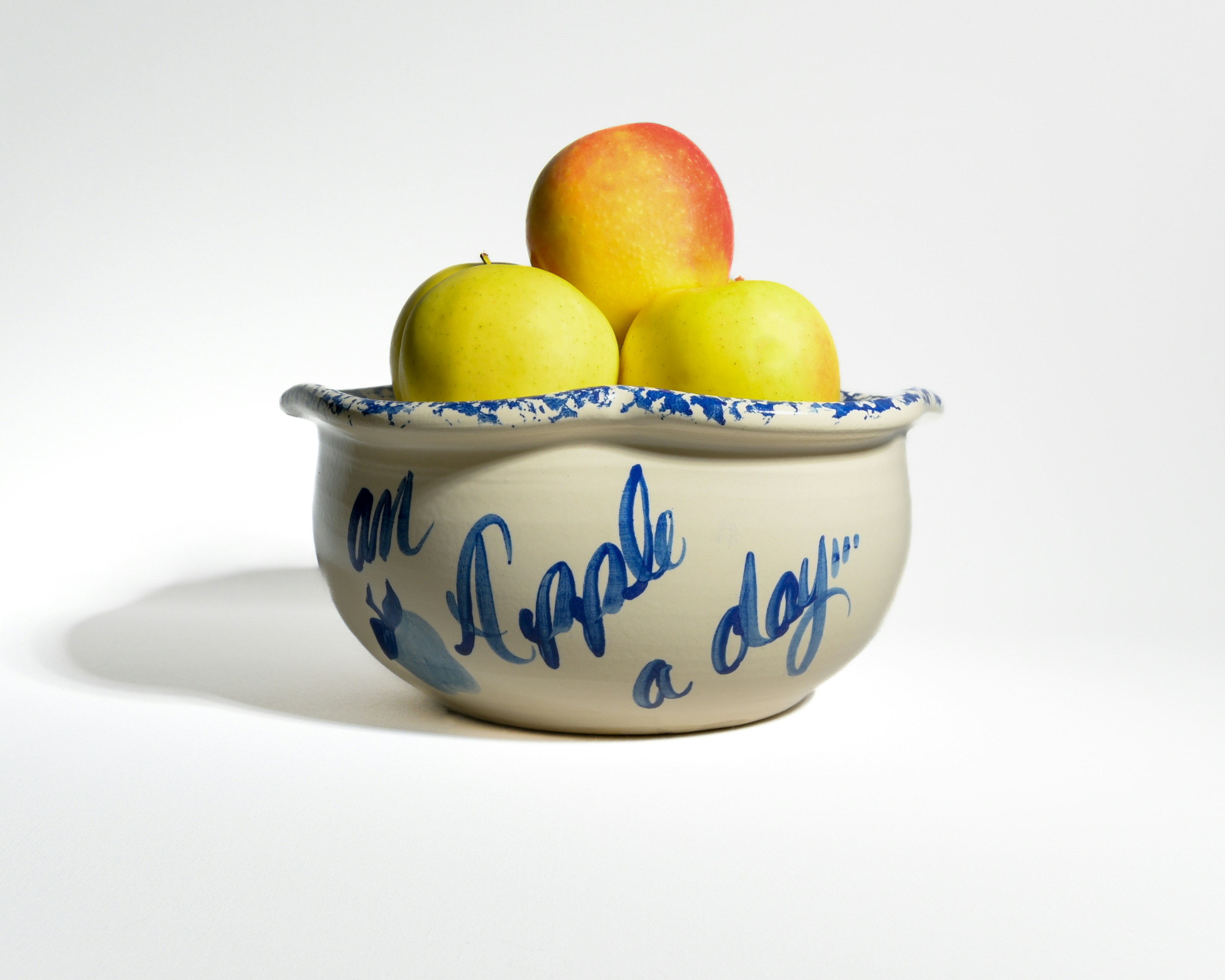 Sunlit Yellow Apples Nest in a Blue-Trimmed Ceramic Bowl
