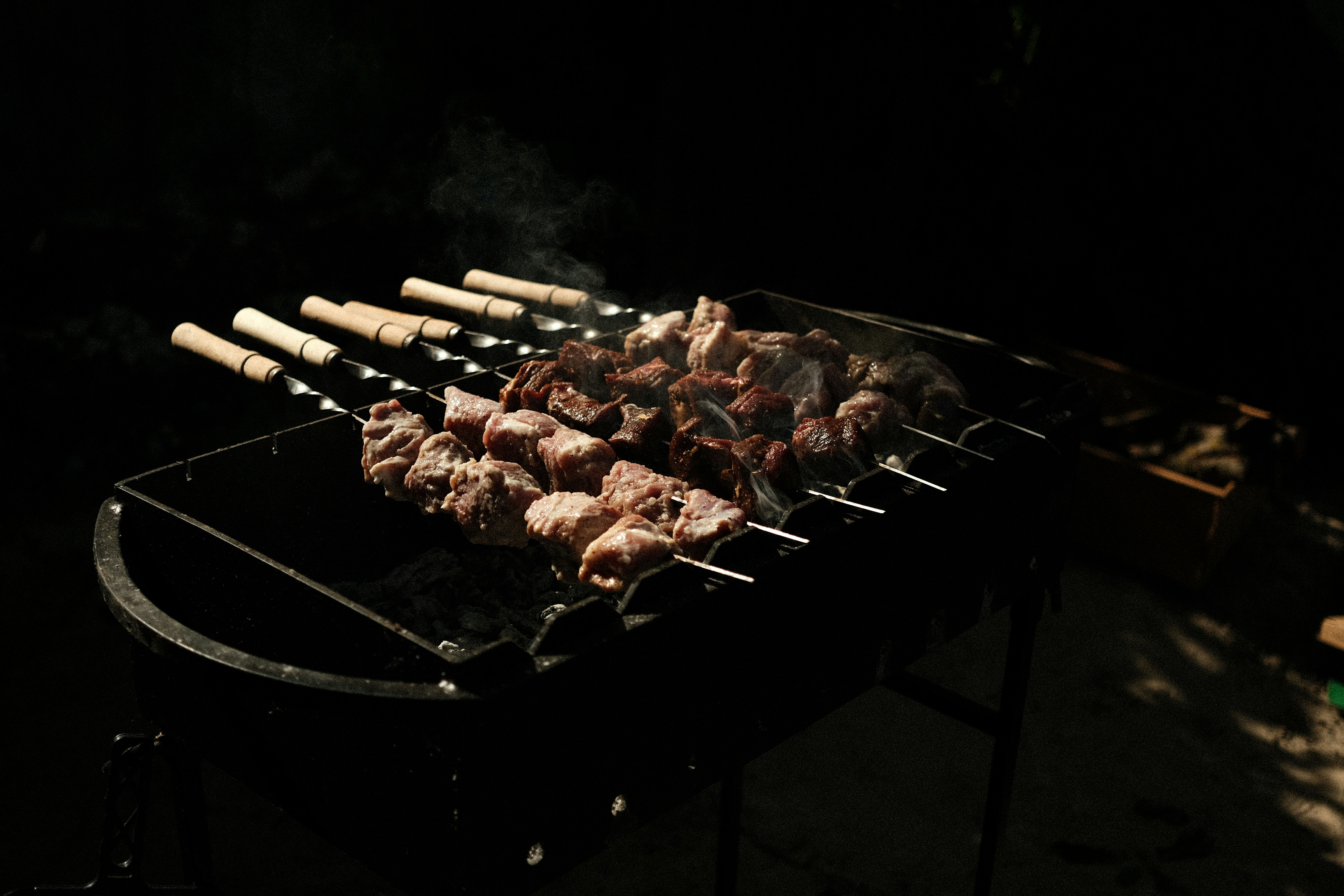 Skewered meat grilling over hot coals.