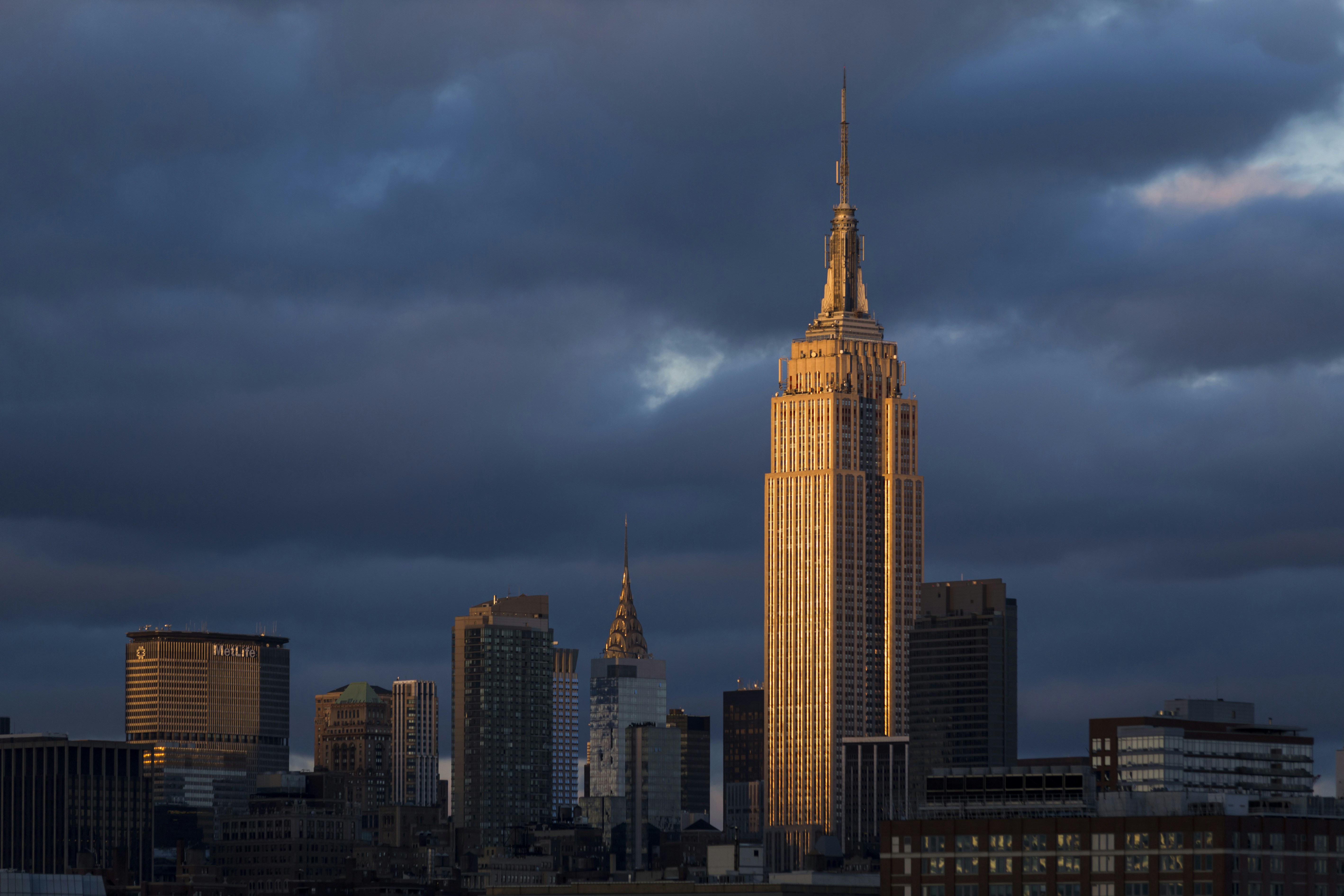 Gilded Peak: Empire State bathed in sunlight against a brooding Manhattan sky