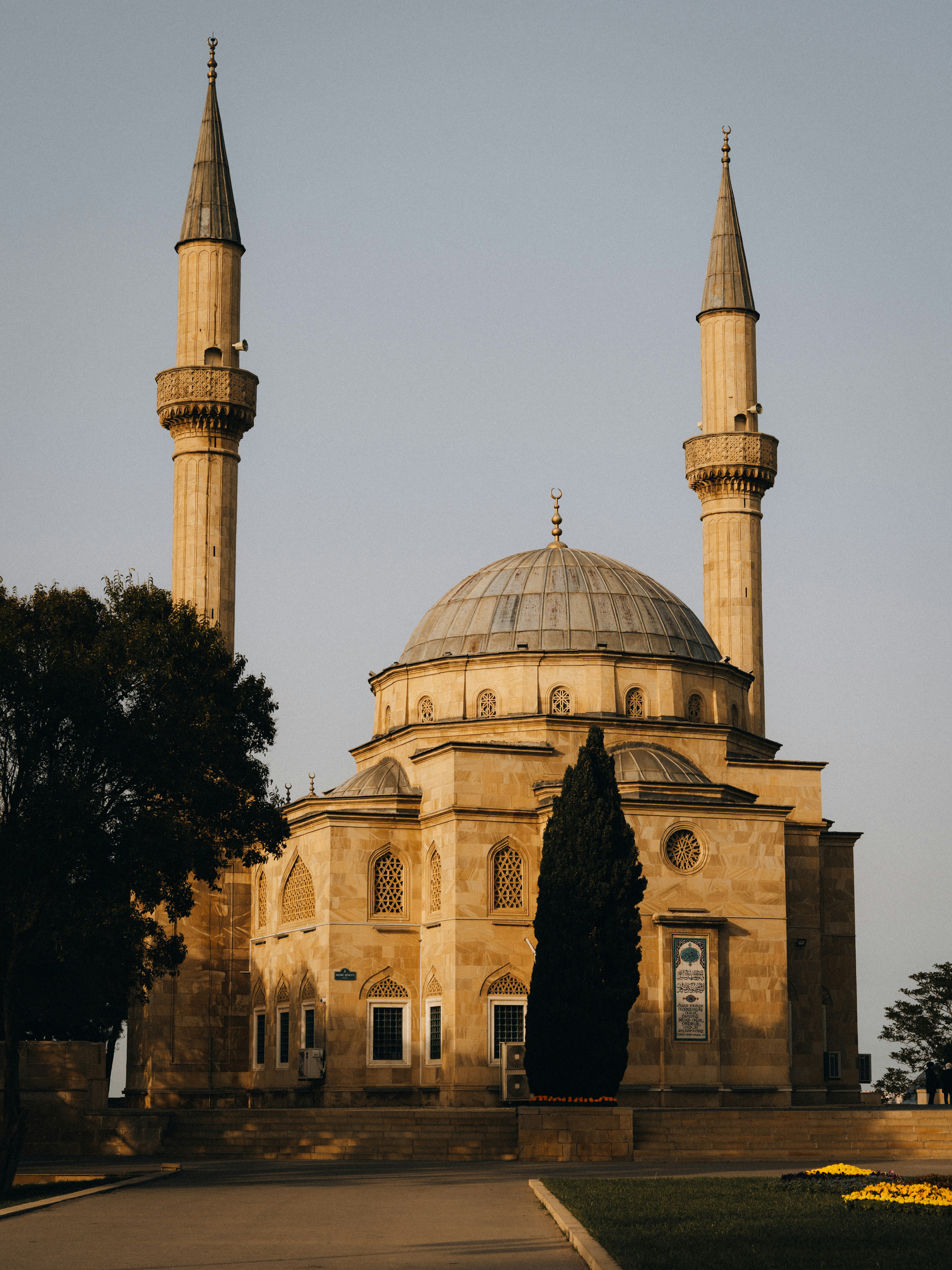 Historic mosque featuring intricate stonework and towering minarets against a soft evening sky.