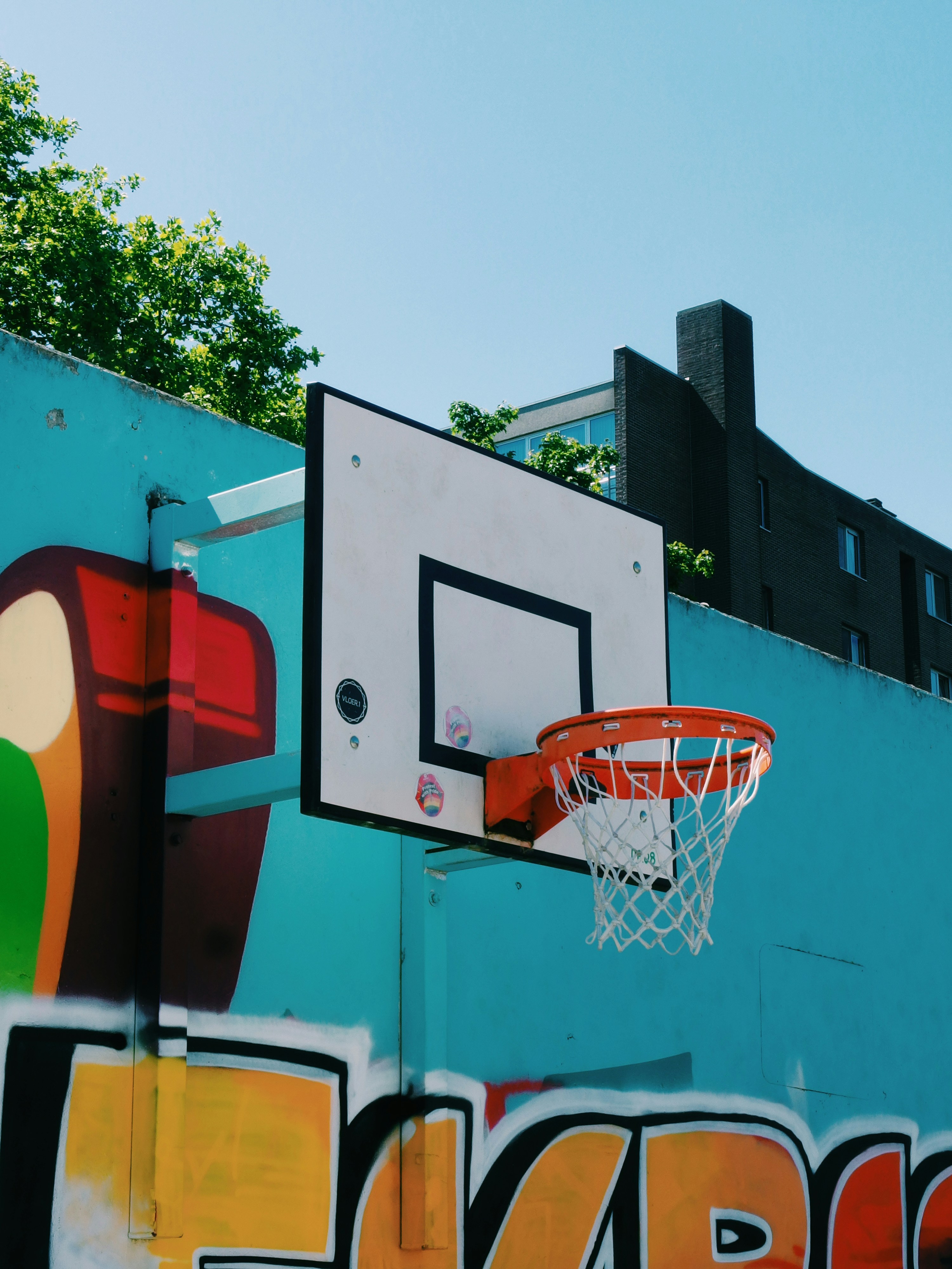 A basketball hoop stands against a graffiti wall.