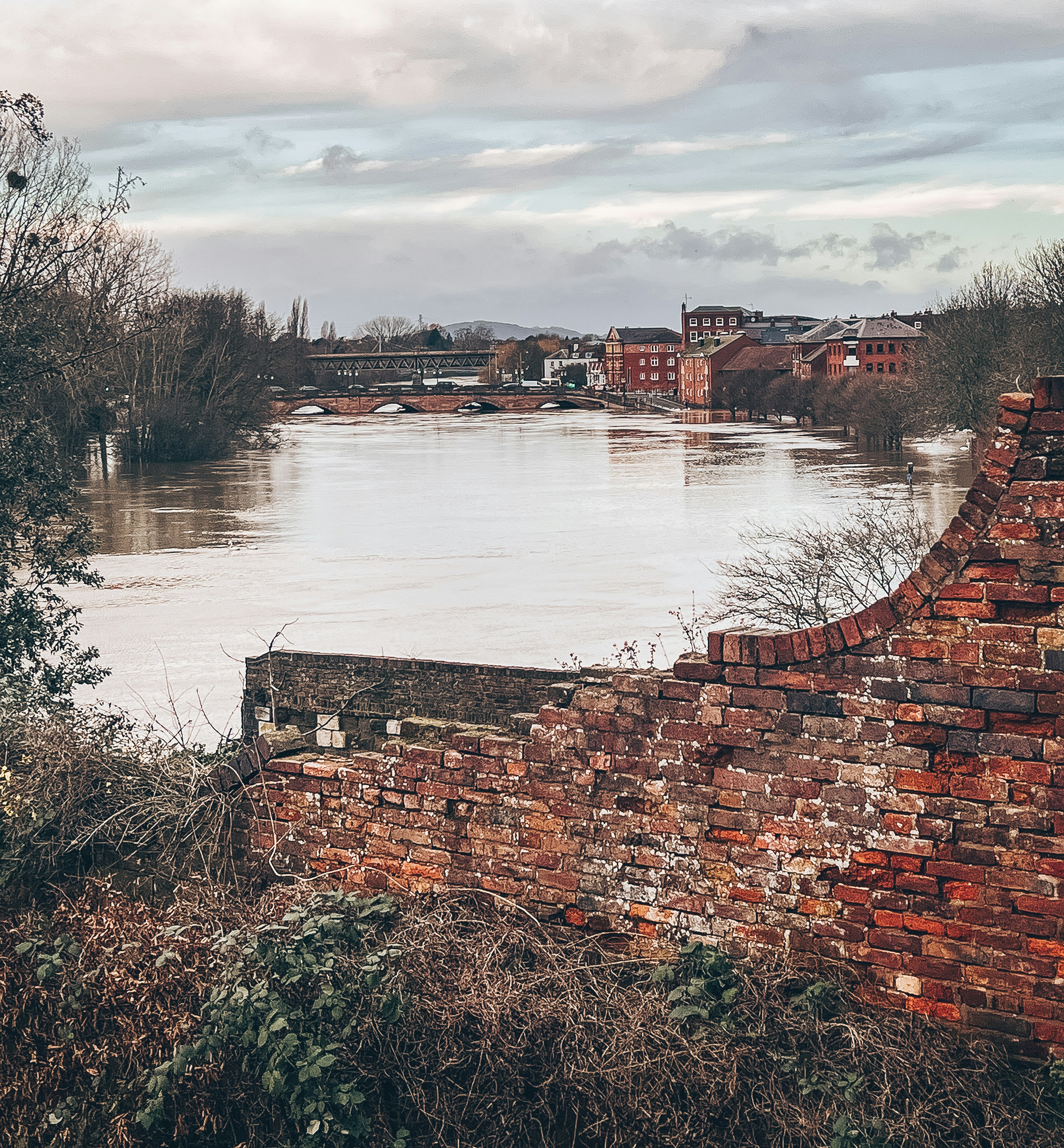 A flooded river flows past old brick buildings. photo – Free Car Image ...