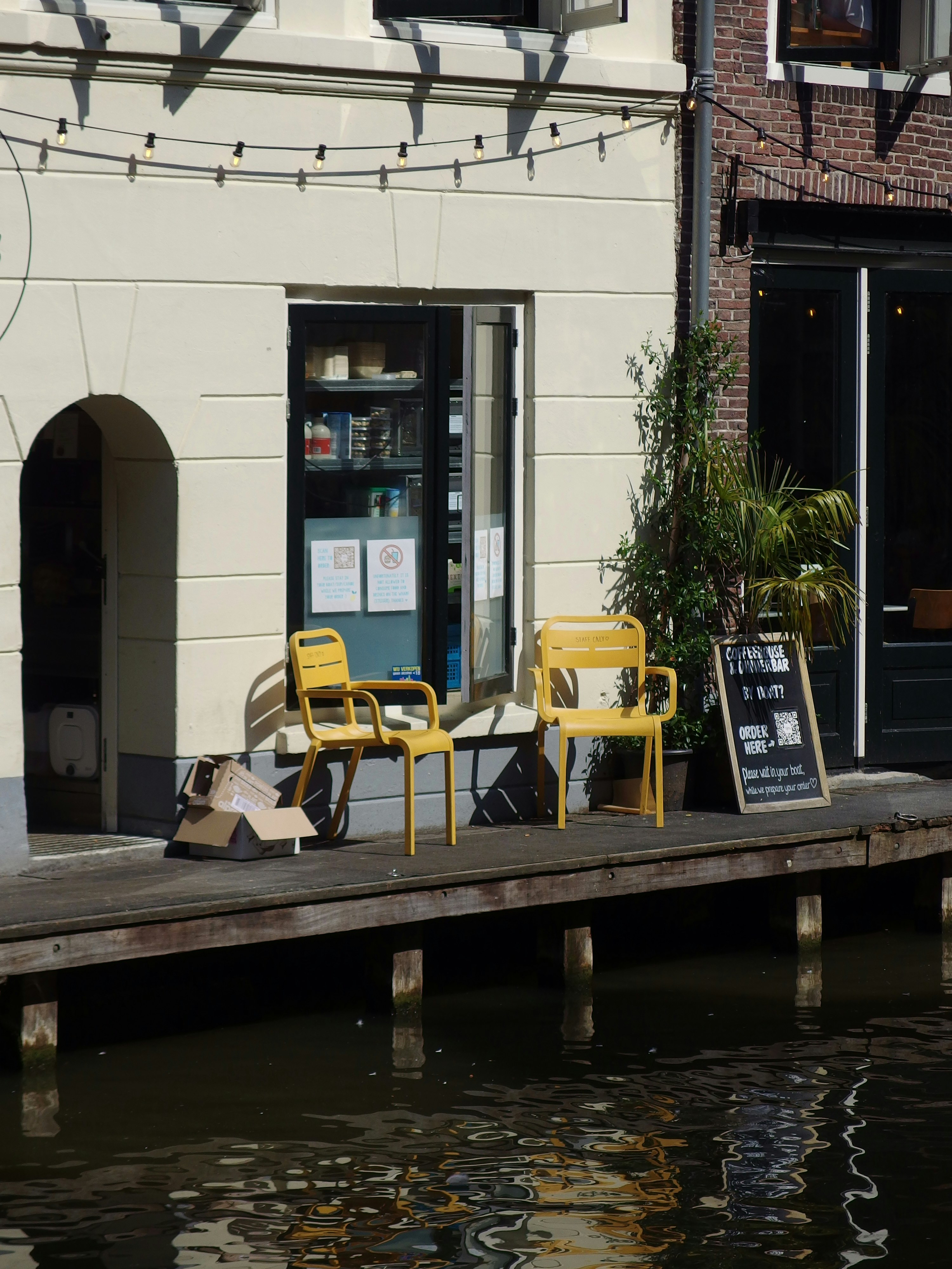 Two yellow chairs sit by a canal shop.