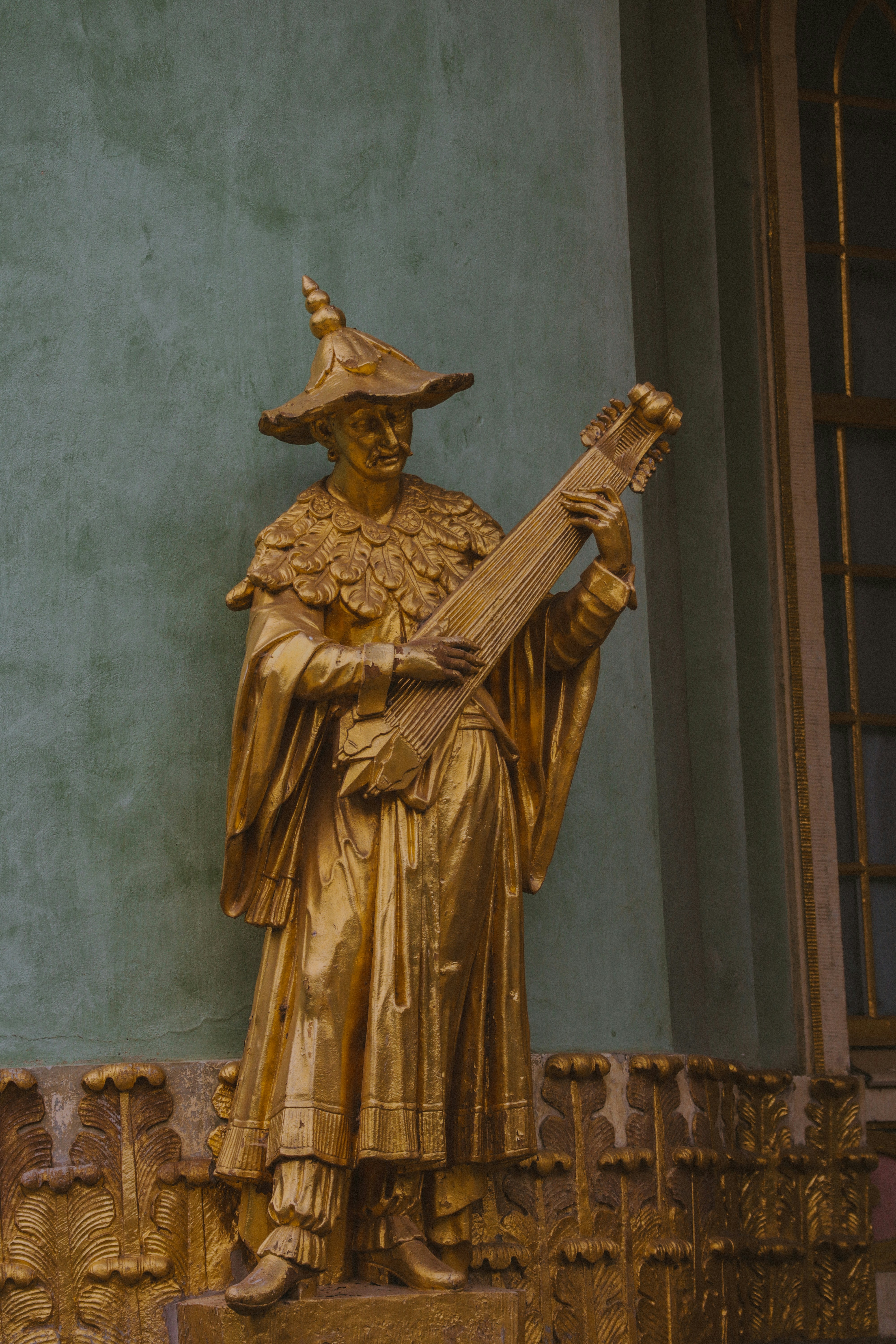 The Gilded Minstrel on a Turquoise Facade
