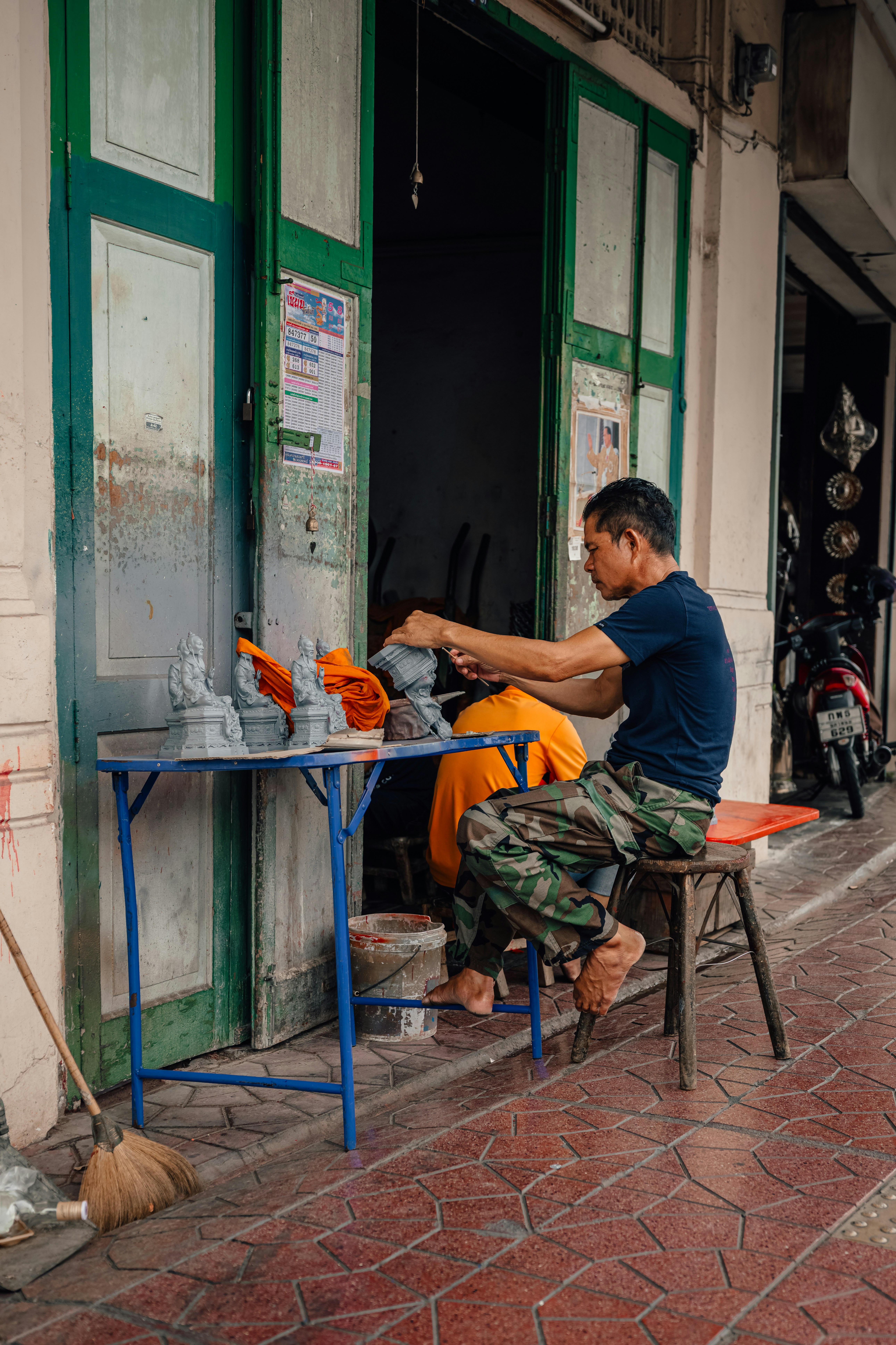 A man sculpts in front of a shop. photo – Free Wallpaper Image on Unsplash