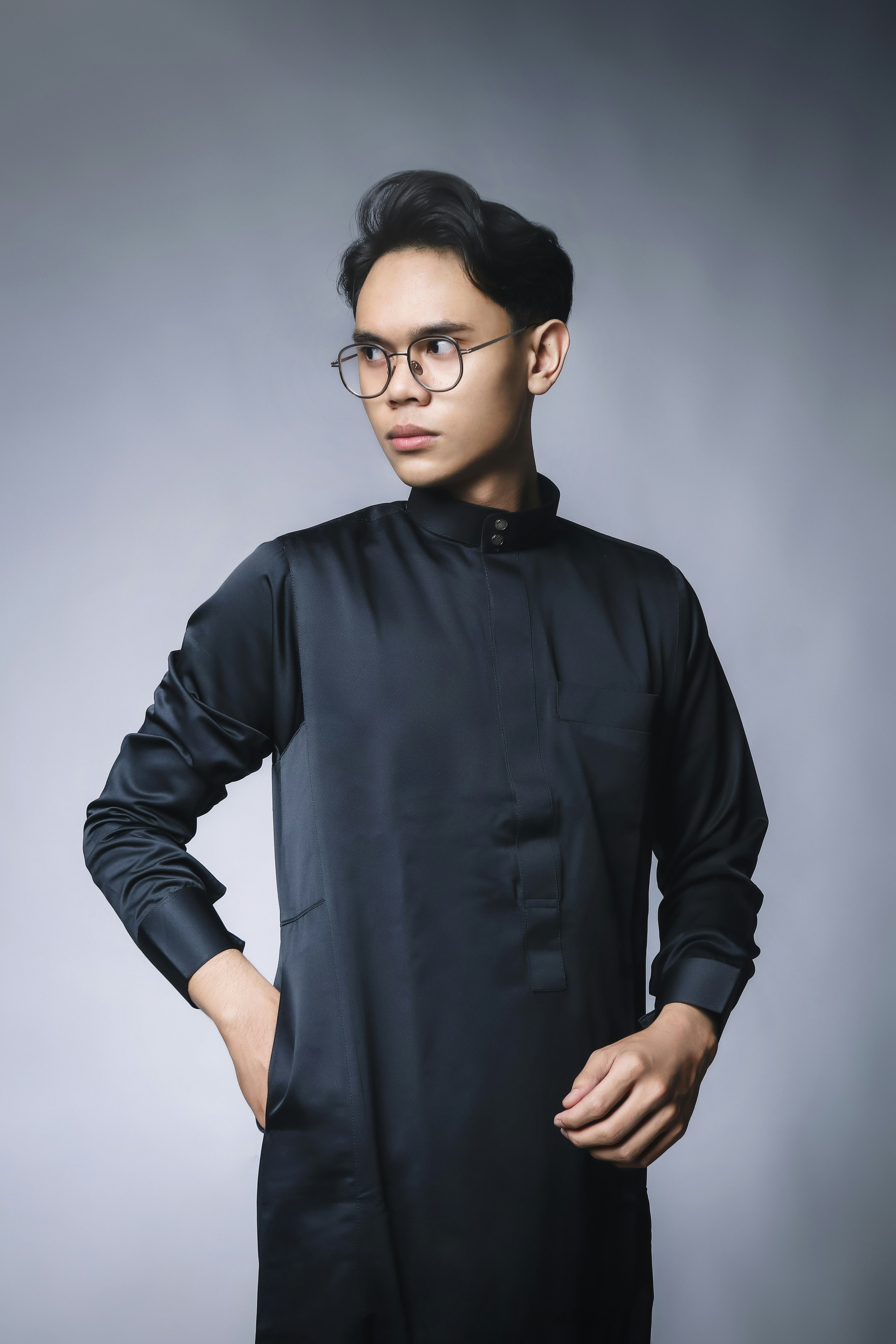 A stylish man in a black outfit poses.