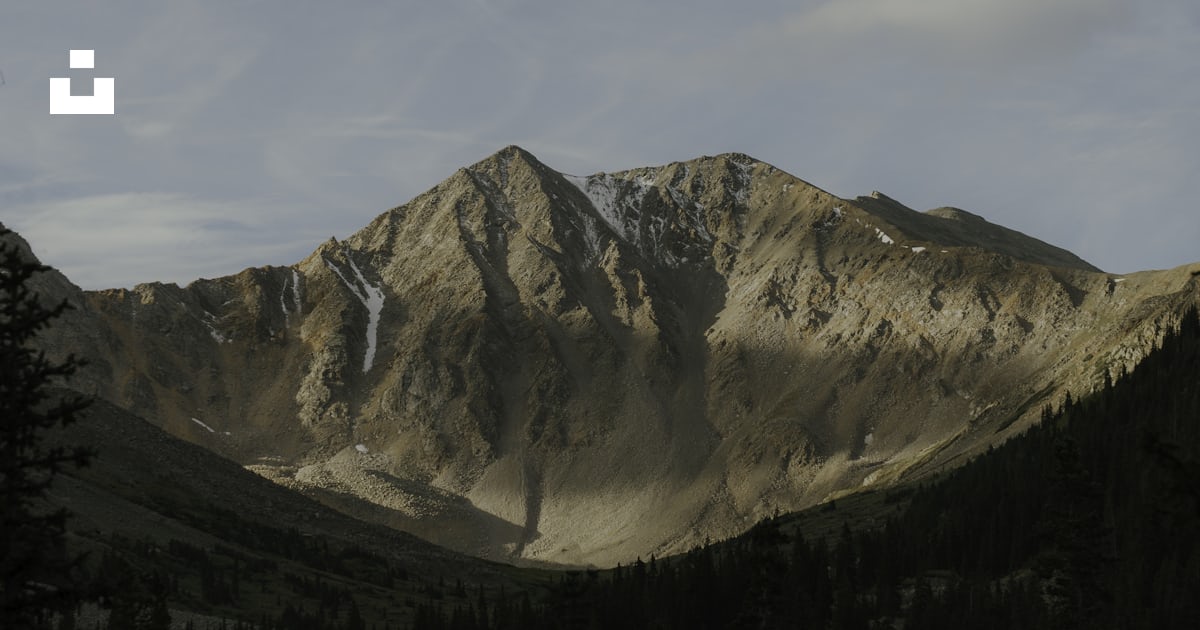 雄大な山々が森林に覆われた谷の上にそびえ立っています。の写真 Unsplashの風景の無料画像