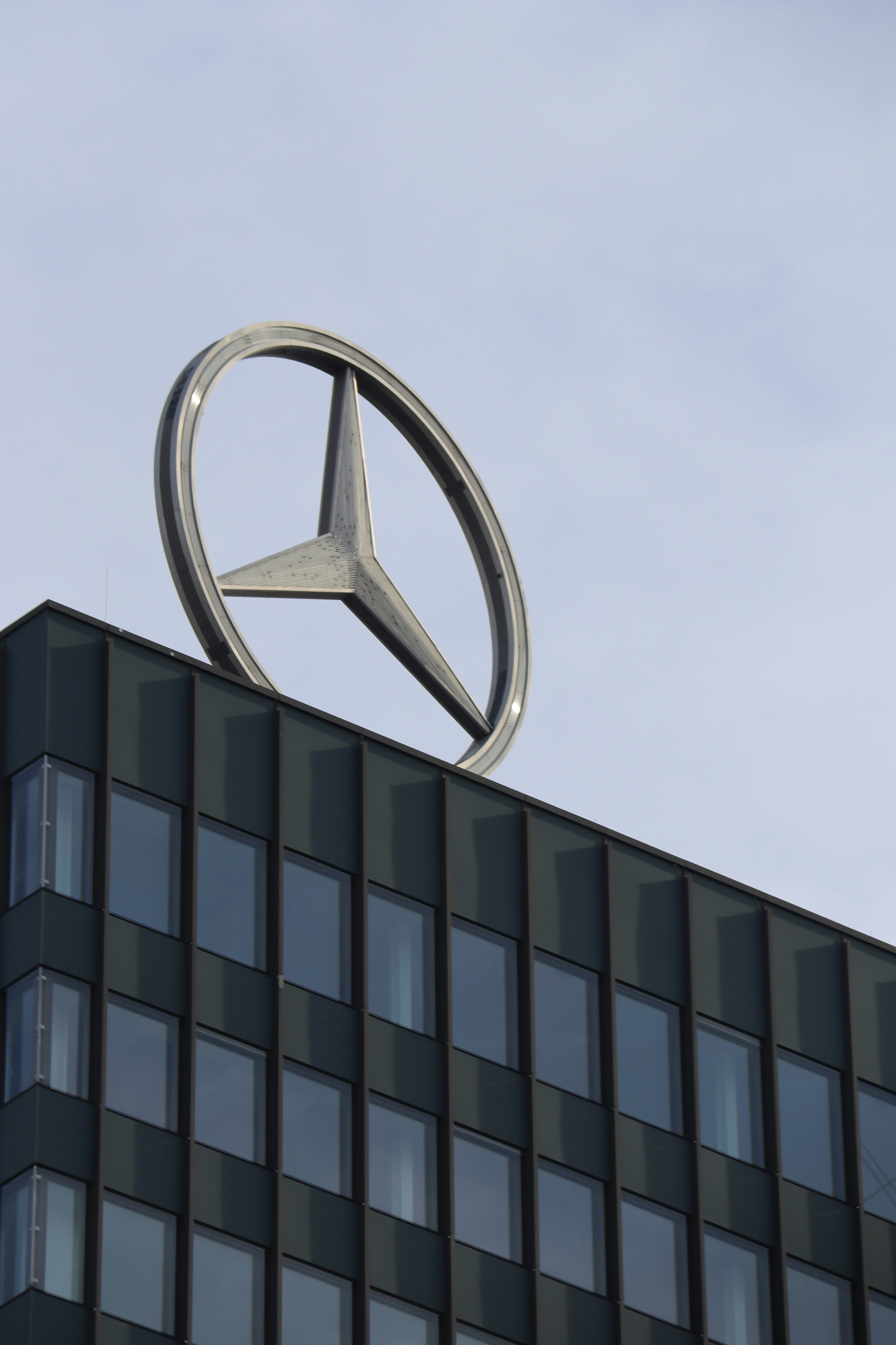 The mercedes-benz logo sits atop a building. photo – Free Building ...