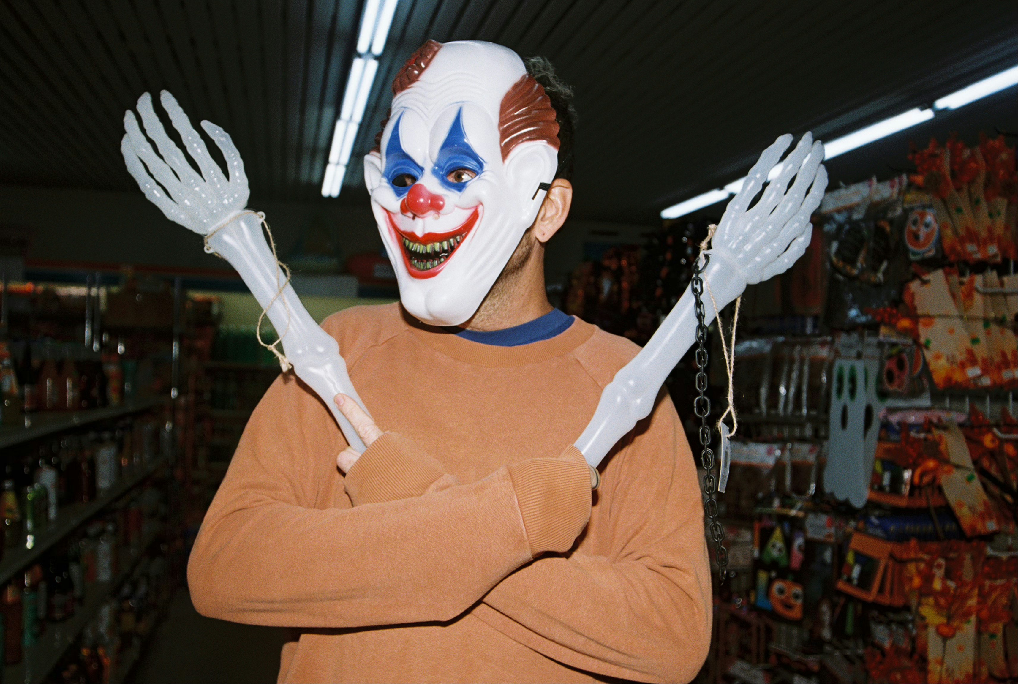 A person in a clown mask holds skeleton arms. photo – Free Halloween ...