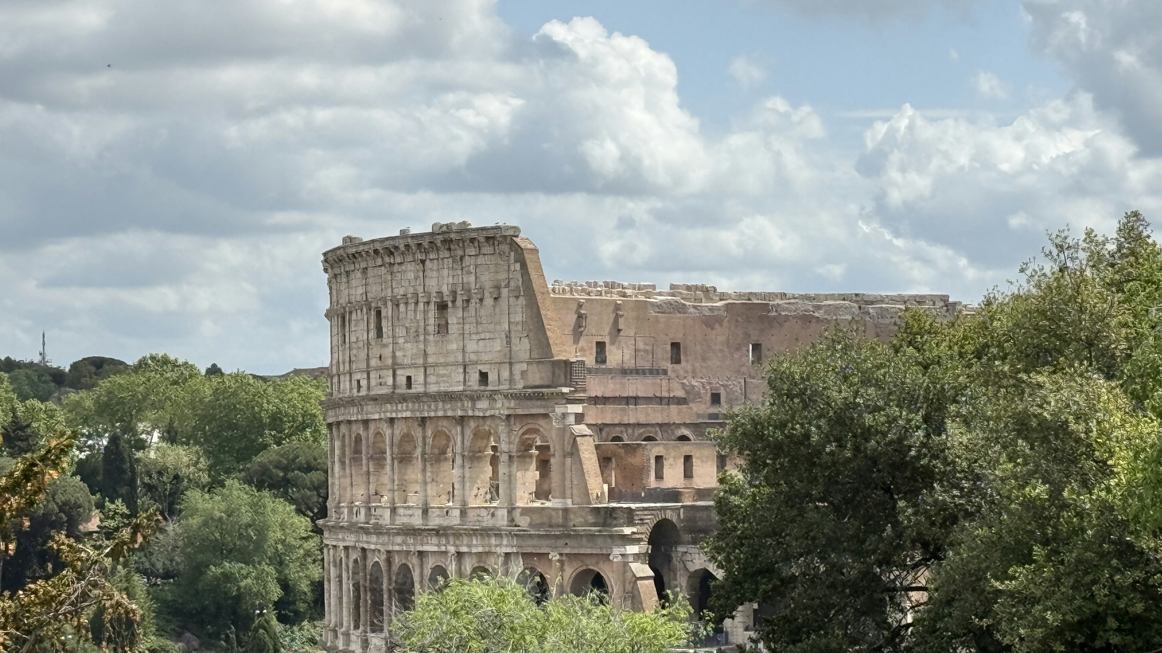 The colosseum stands majestically under a cloudy sky.