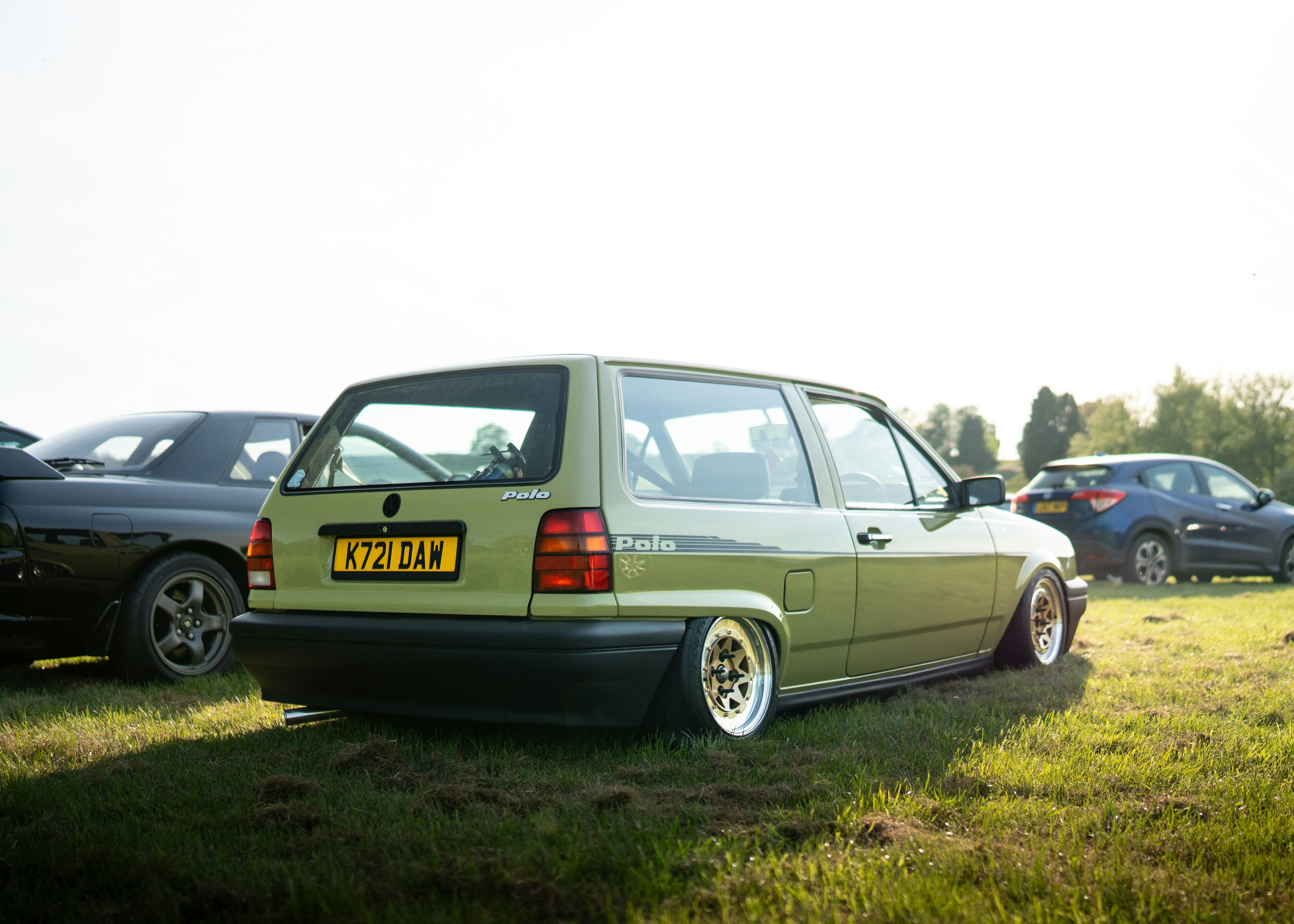 Classic green Volkswagen Polo parked on grass, showcasing its unique stance and vintage appeal.