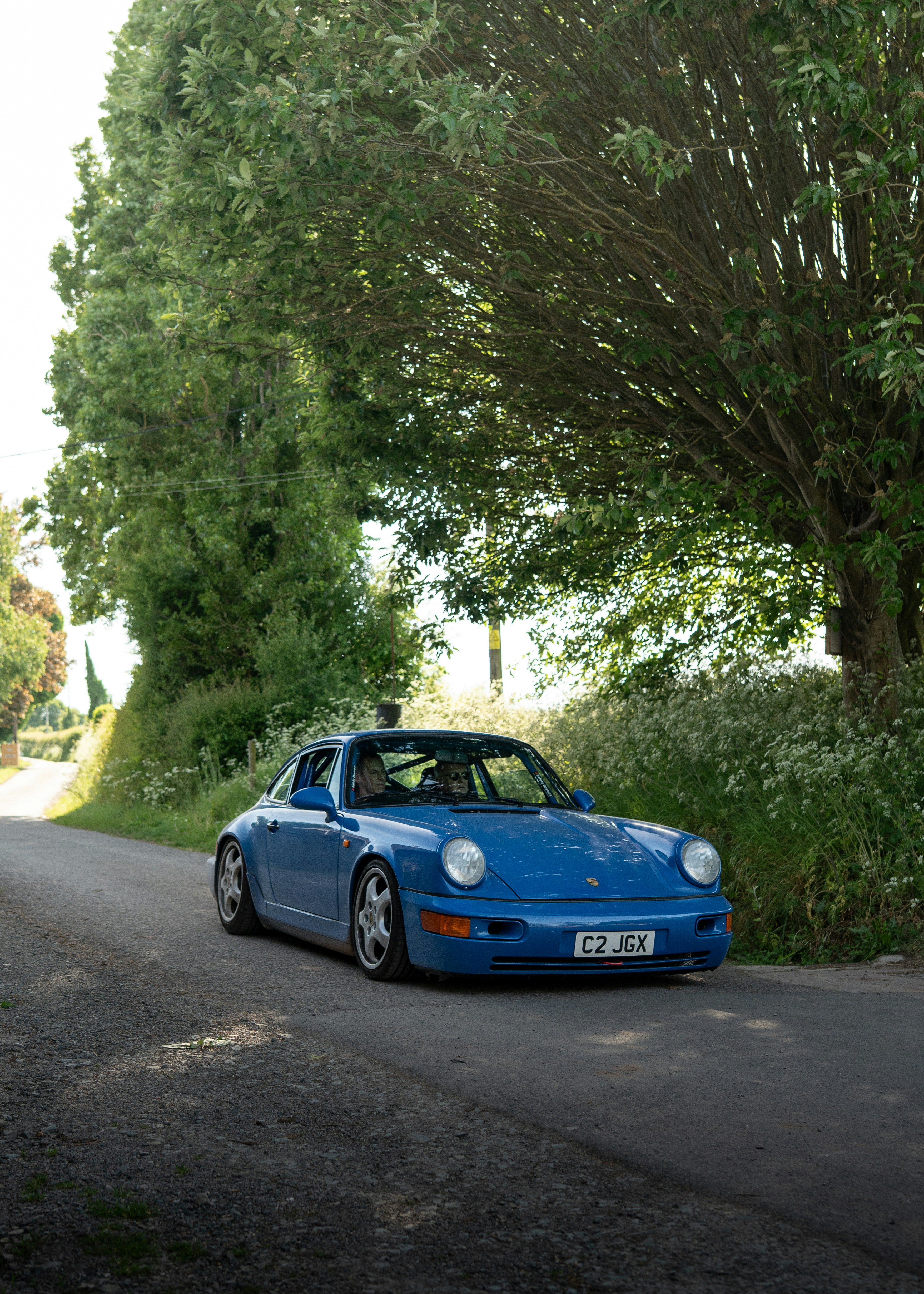 風光明媚な道路を走るブルーポルシェ。の写真 – Unsplashの車の無料画像