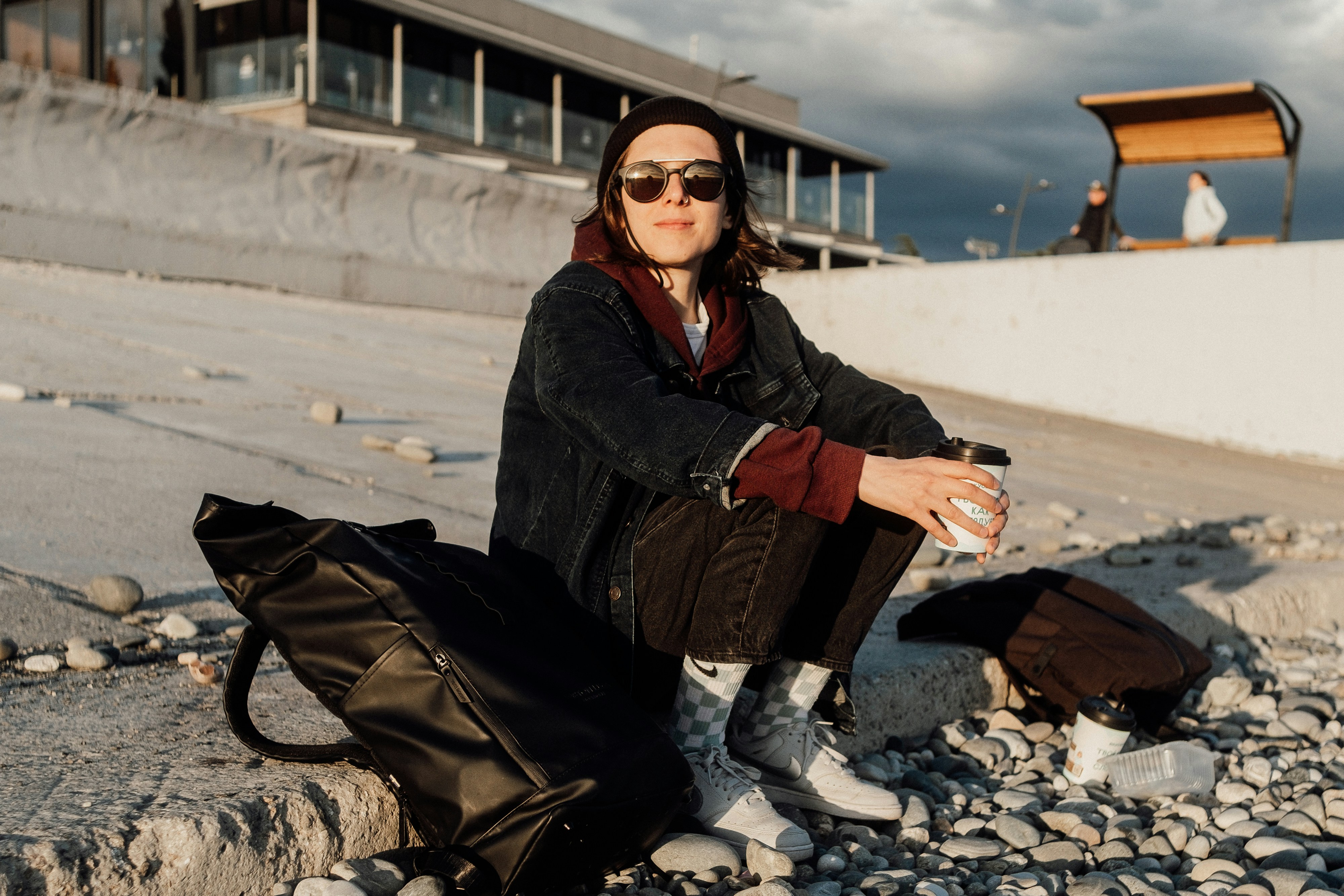 A person with sunglasses sits on the beach.
